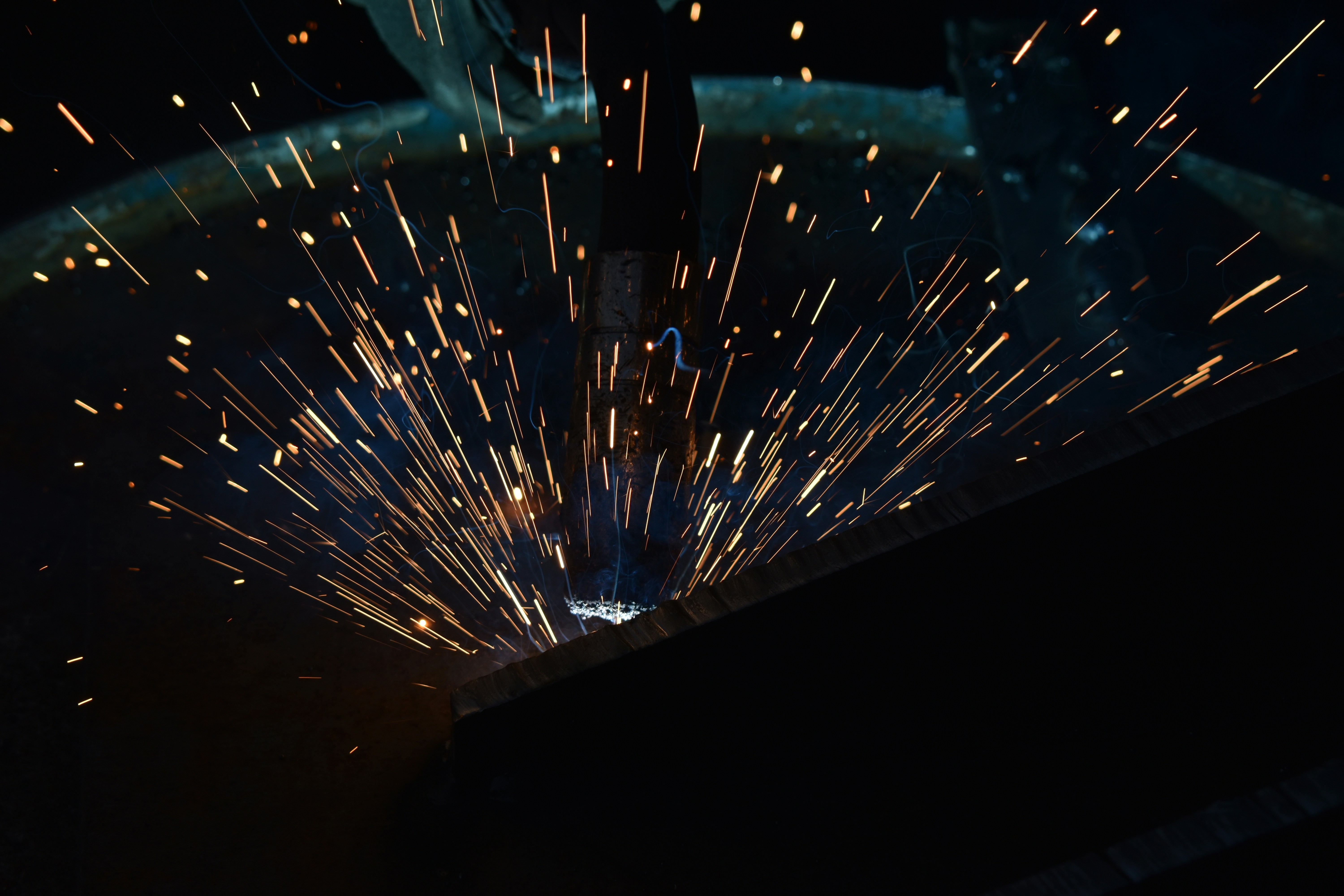 Sparks erupt from a welding torch, illuminating the dark surroundings with a burst of energy and creativity.