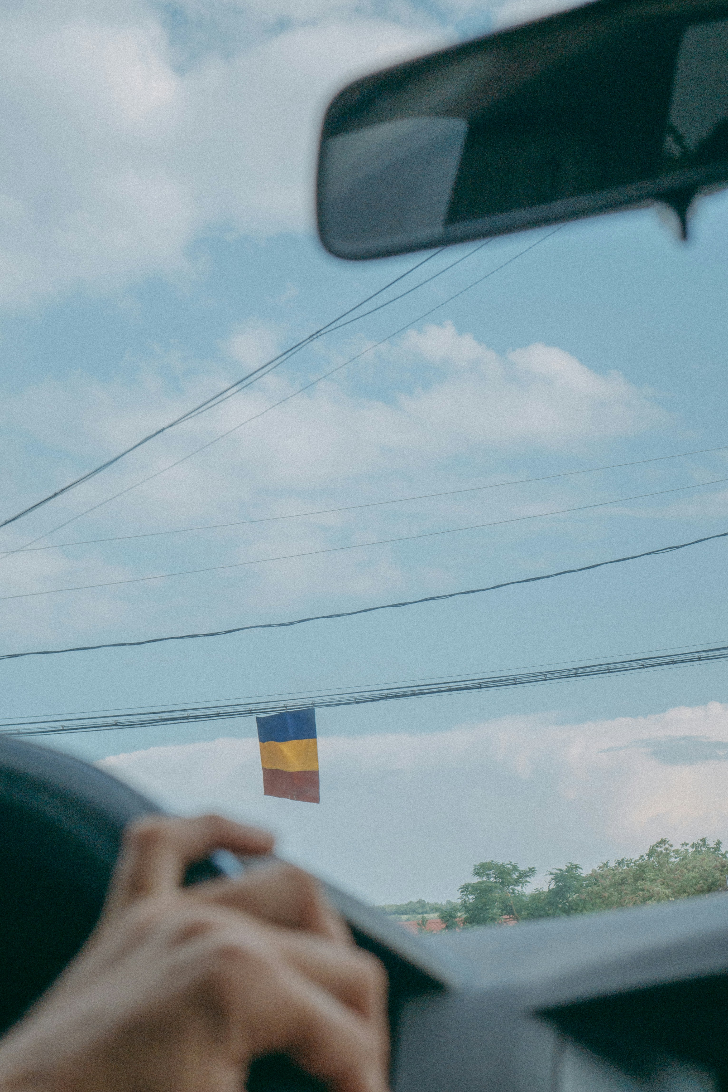Beyond the Glass: A Romanian Flag Framed by a Driver's View