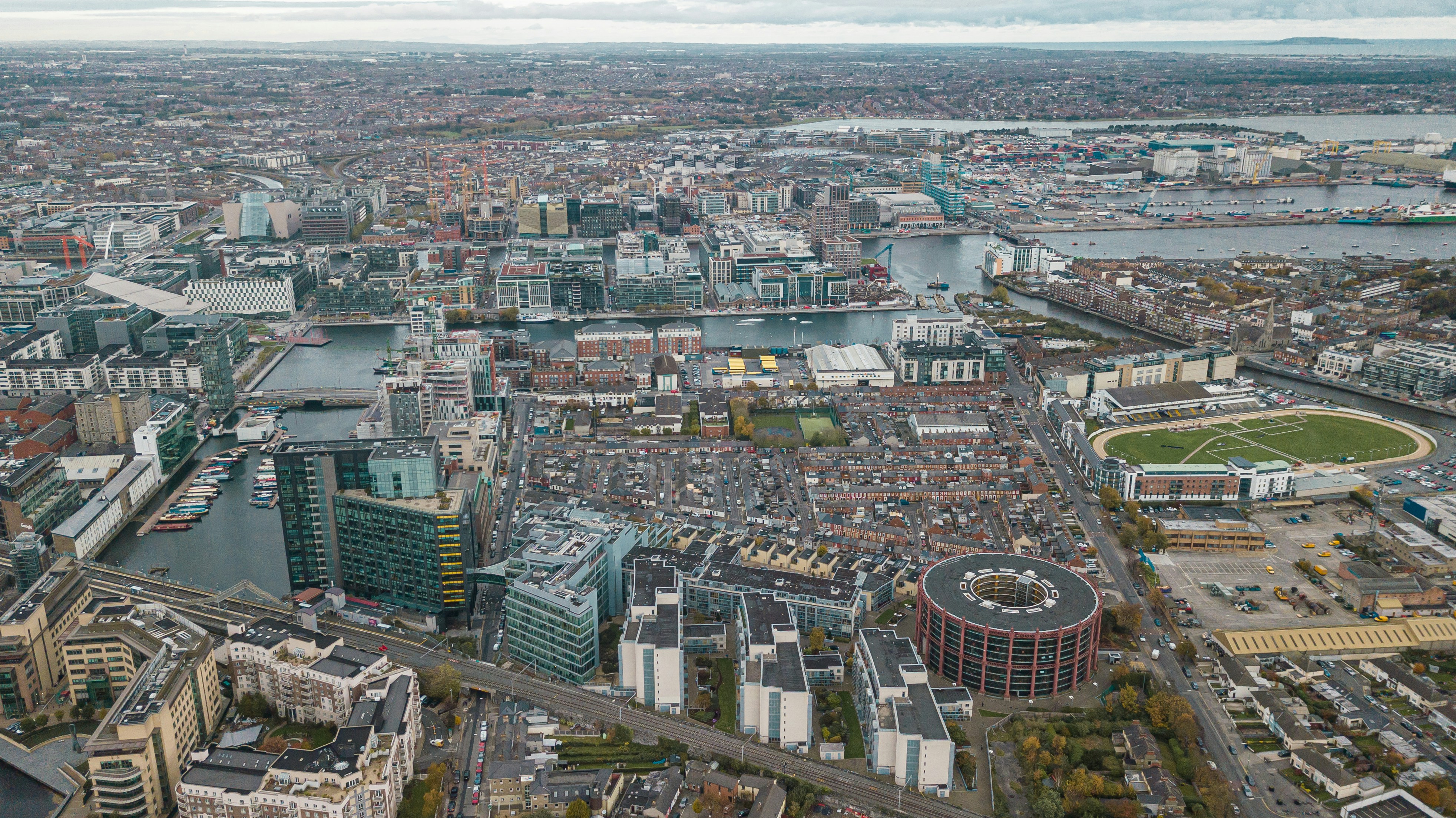 Aerial view of a sprawling cityscape with modern buildings and a river winding through the urban environment.