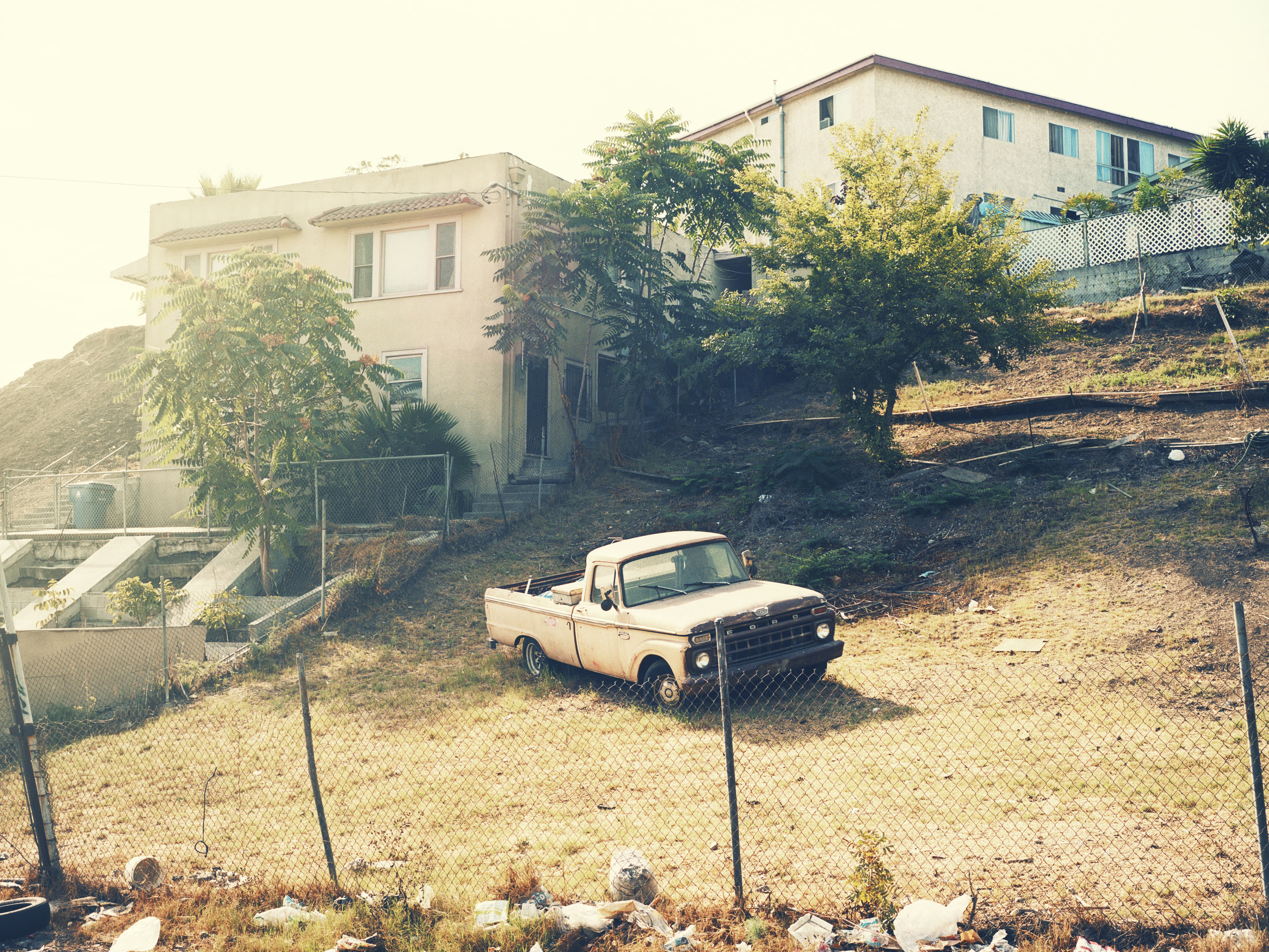 Sunlit hillside yard cradling a vintage pickup beside a weathered house