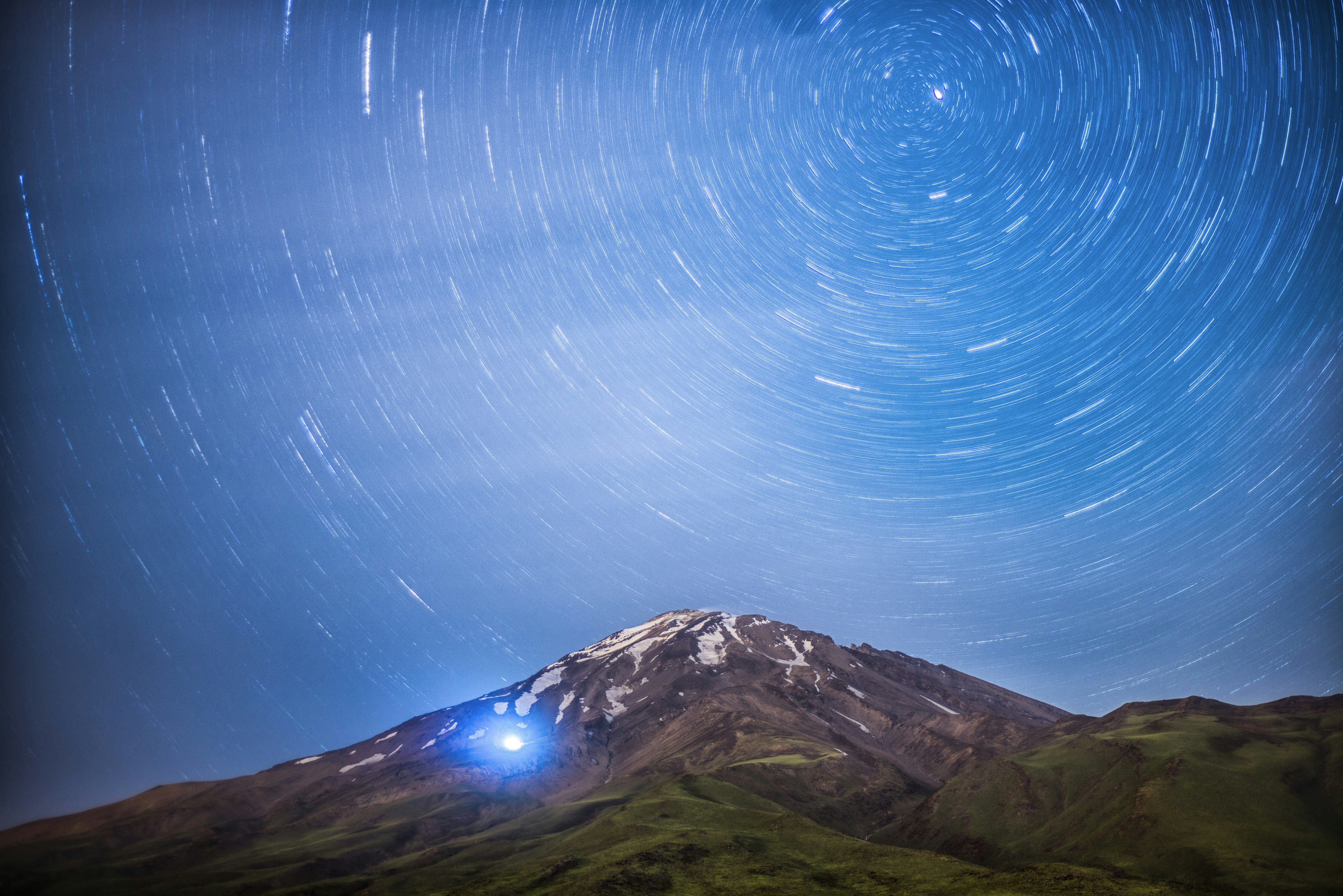 Star trails swirl above Mount Damavand under a clear night sky.