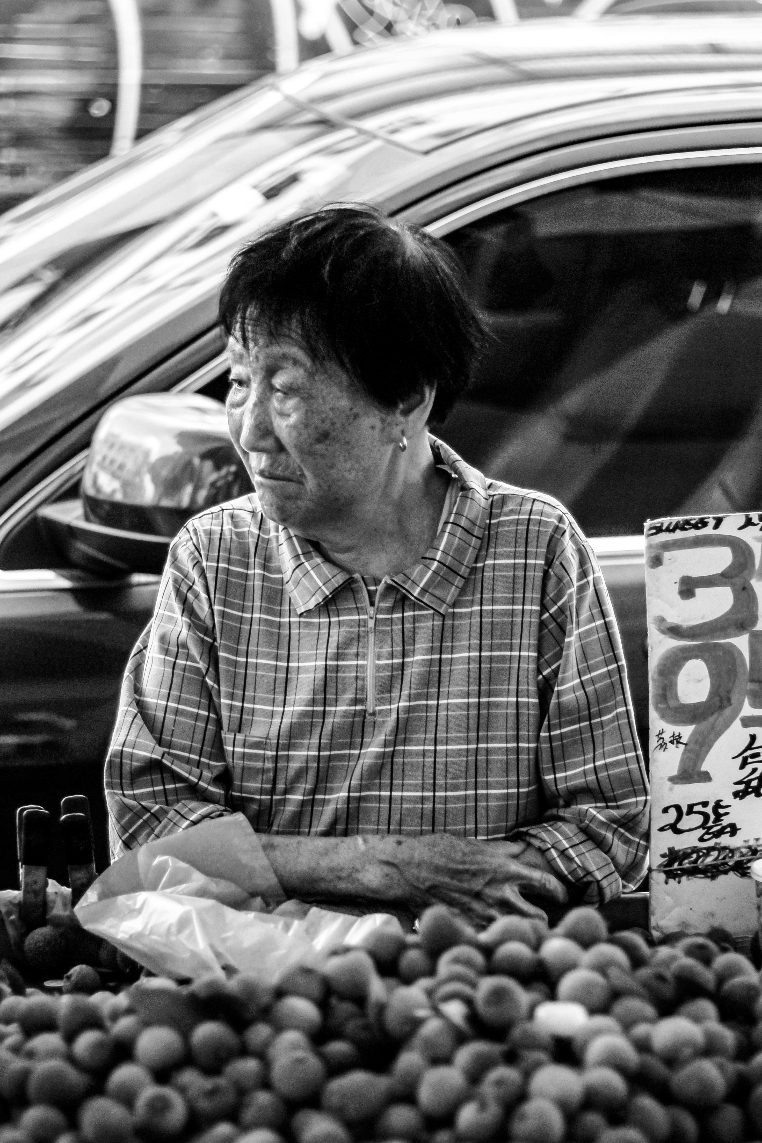 Market Gaze: An Elder Vendor Framed by Fruit and Street Steel