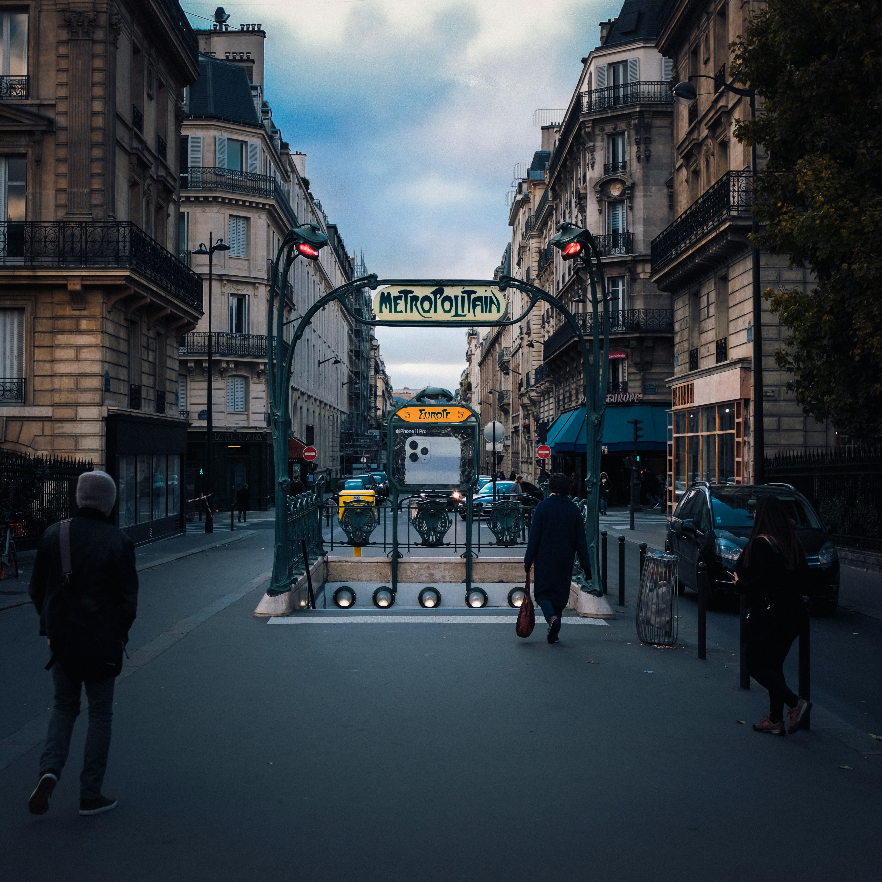 Archway of Transit: A Yellow Tram Anchors a Parisian Boulevard Under the Métro Sign