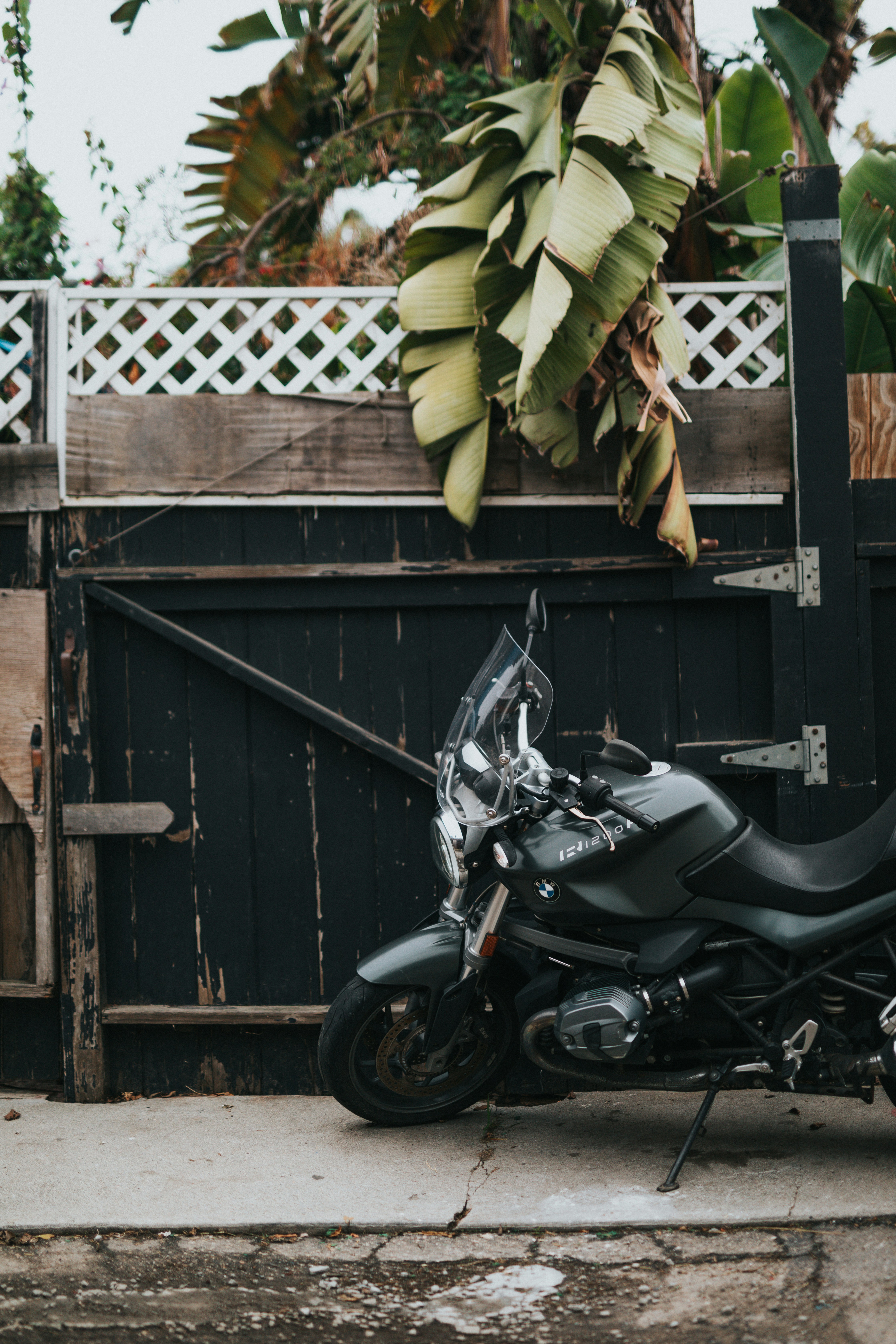 Midnight Guardian: A BMW Motorcycle Resting Against a Weathered Gate