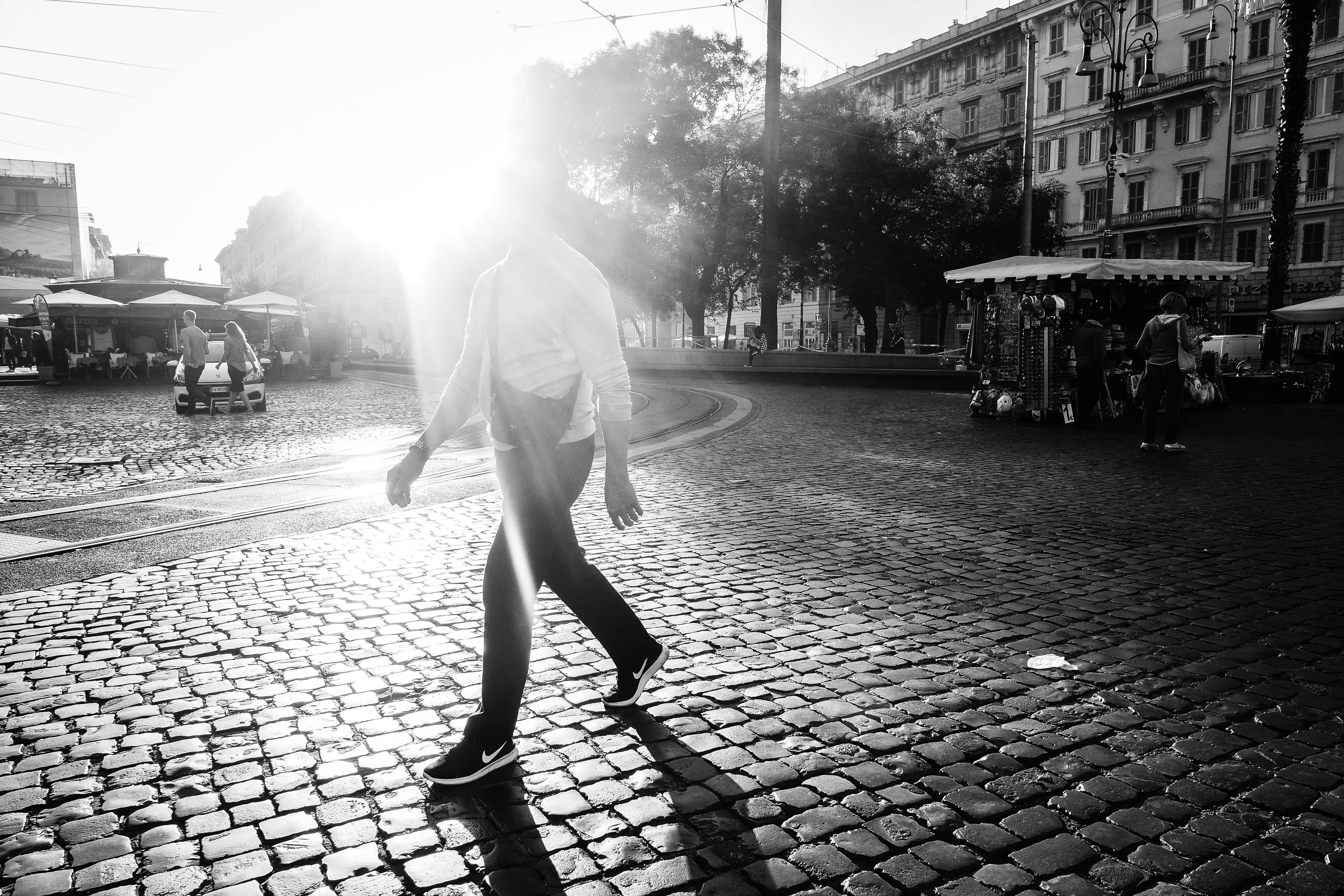 Grayscale photo of man walking on brick pavement photo – Free Walkway ...