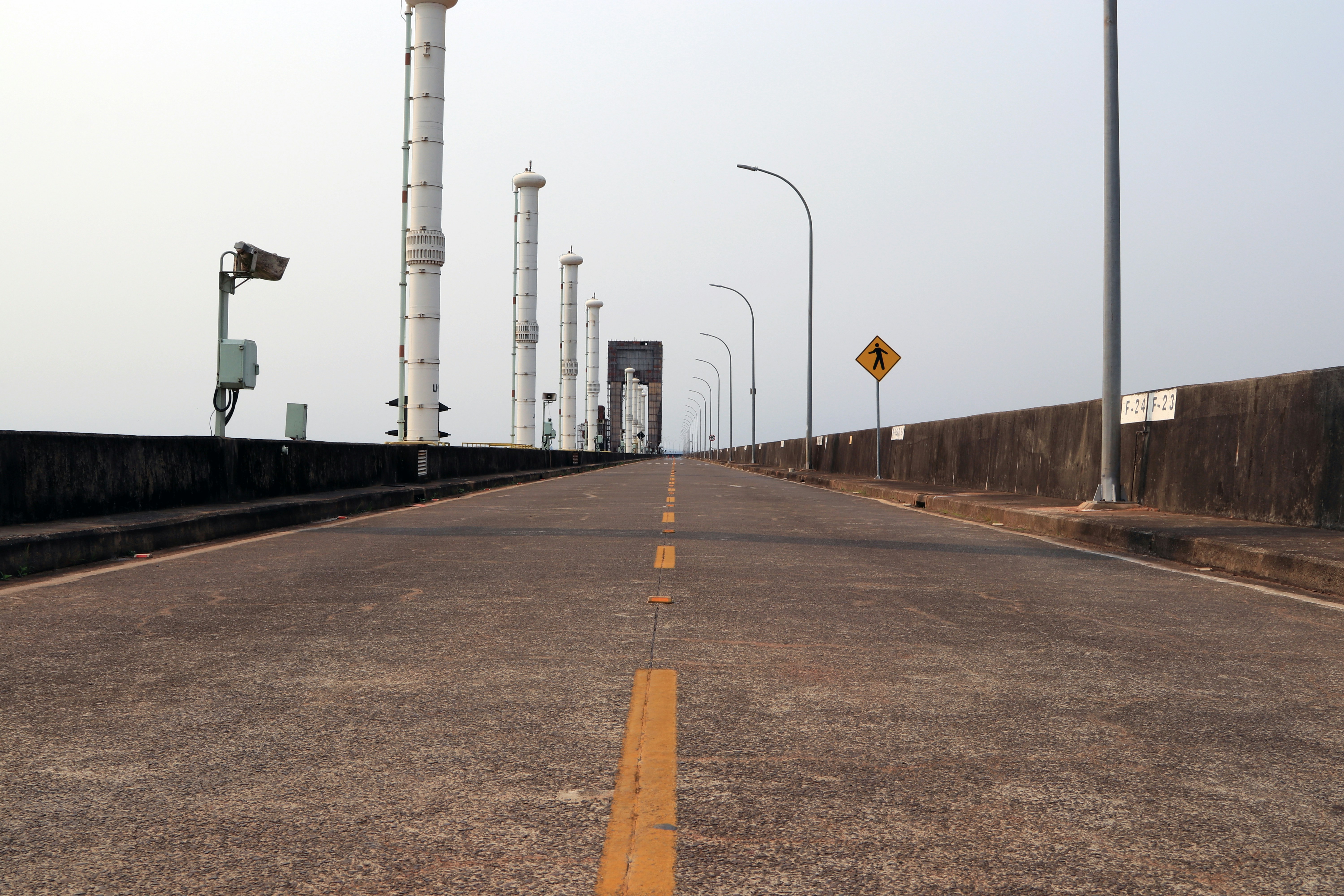 A long, empty road flanked by tall structures, leading towards a distant horizon. The scene evokes a sense of anticipation and exploration.