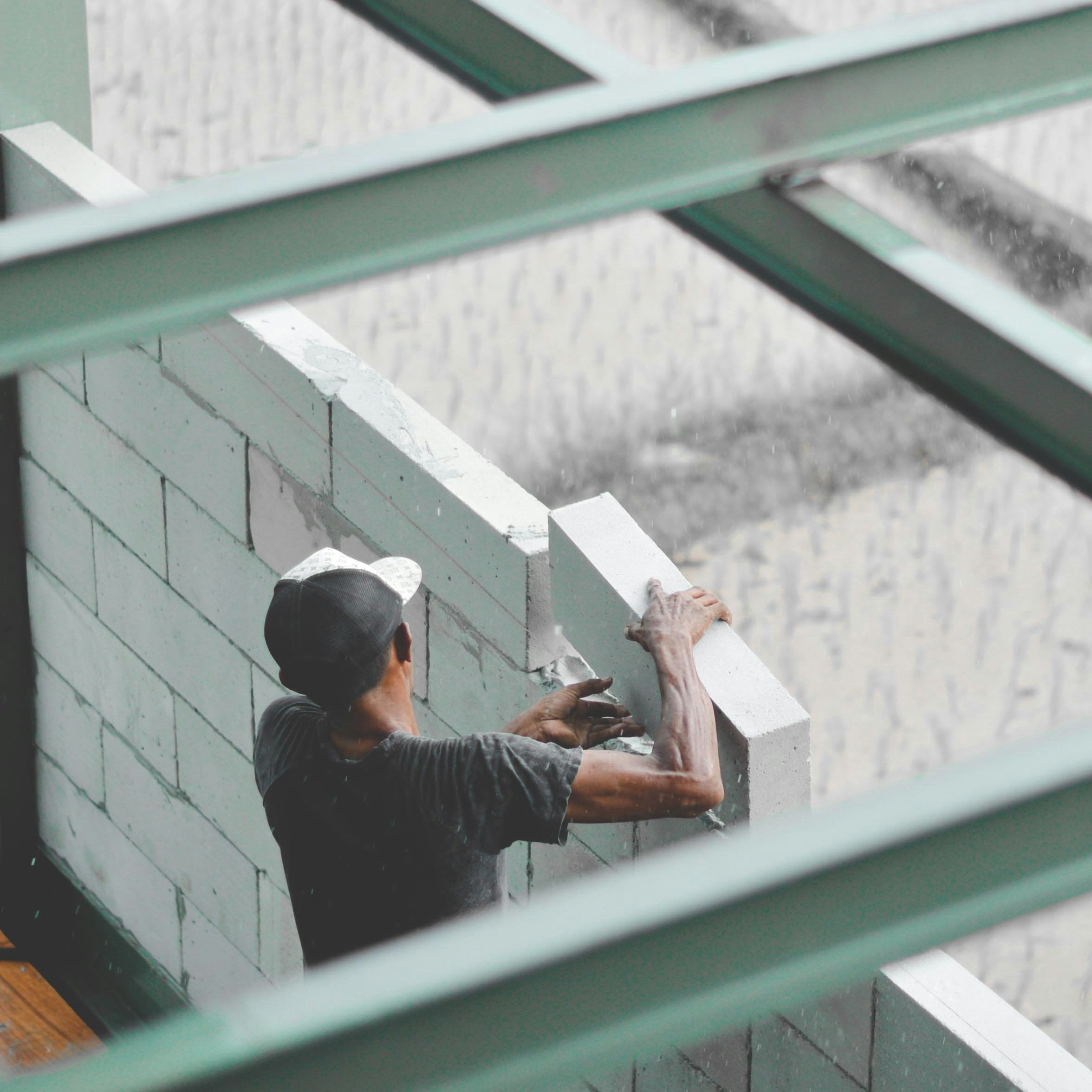 Foto Hombre poniendo bloques en la pared – Imagen Gris gratis en Unsplash