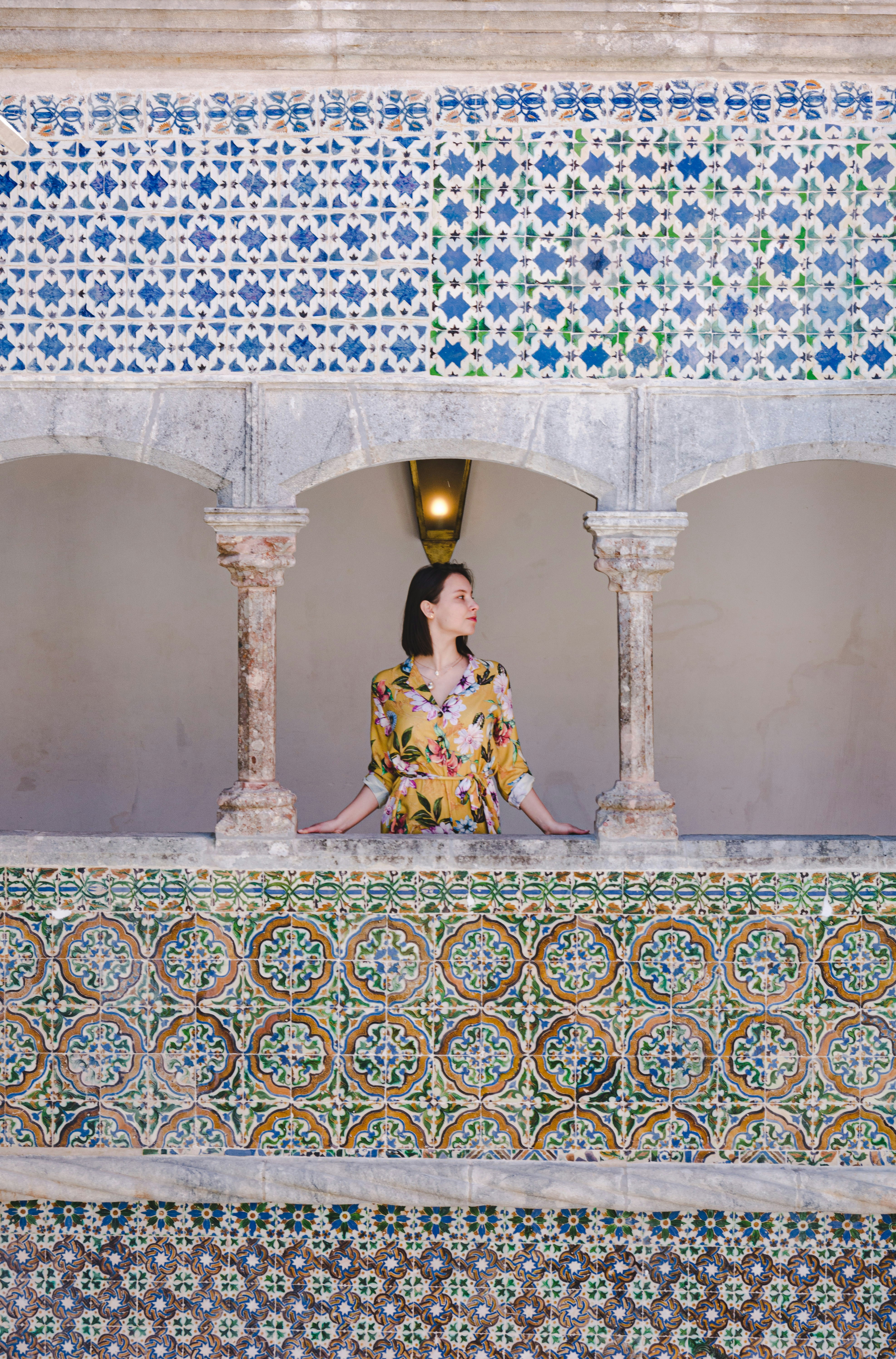 Portrait in a Tile-Colonnade: Woman in Yellow Floral Dress Between Arched Pillars