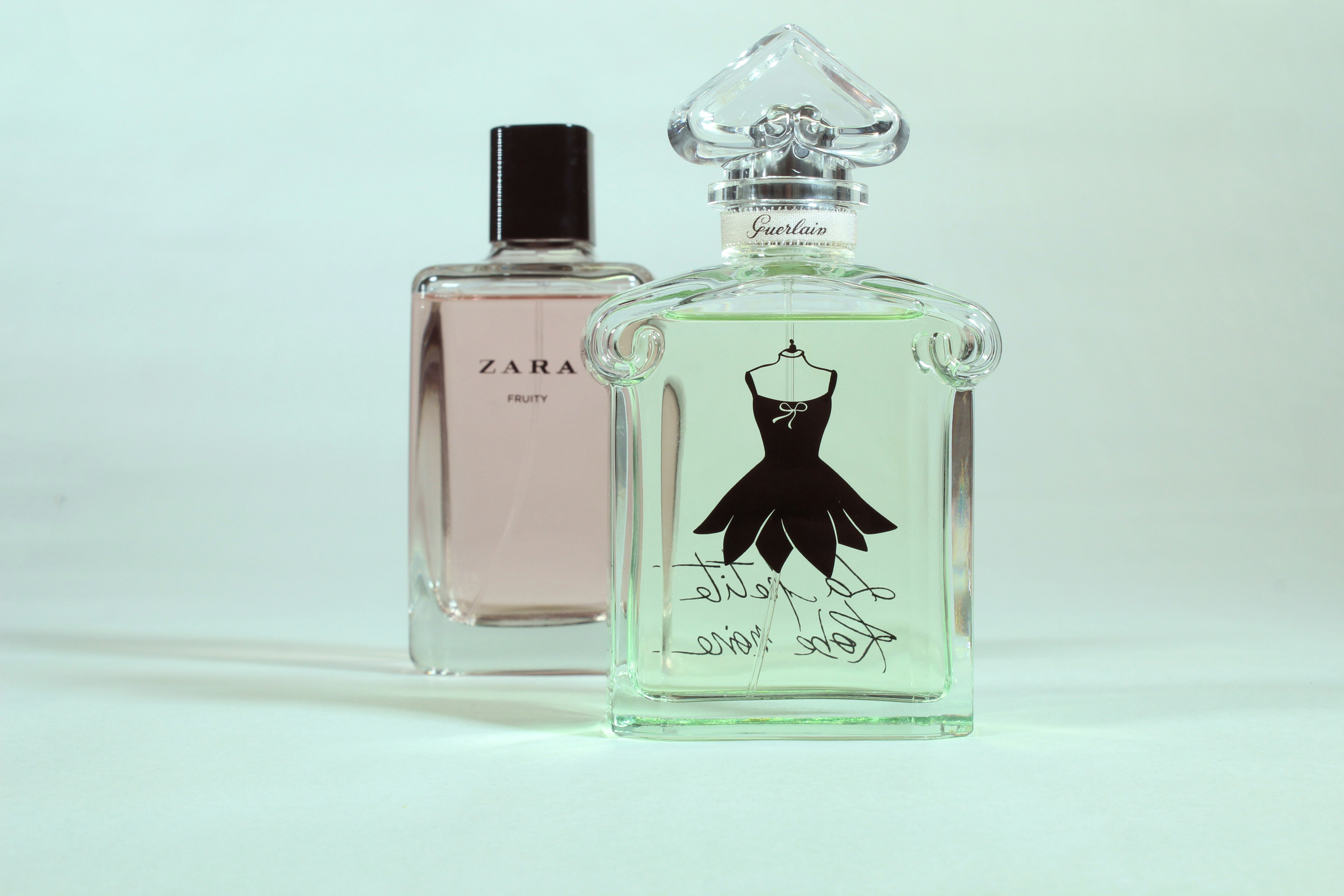 Two perfume bottles, one from Zara and the other featuring a dress silhouette design, are elegantly displayed against a soft background.
