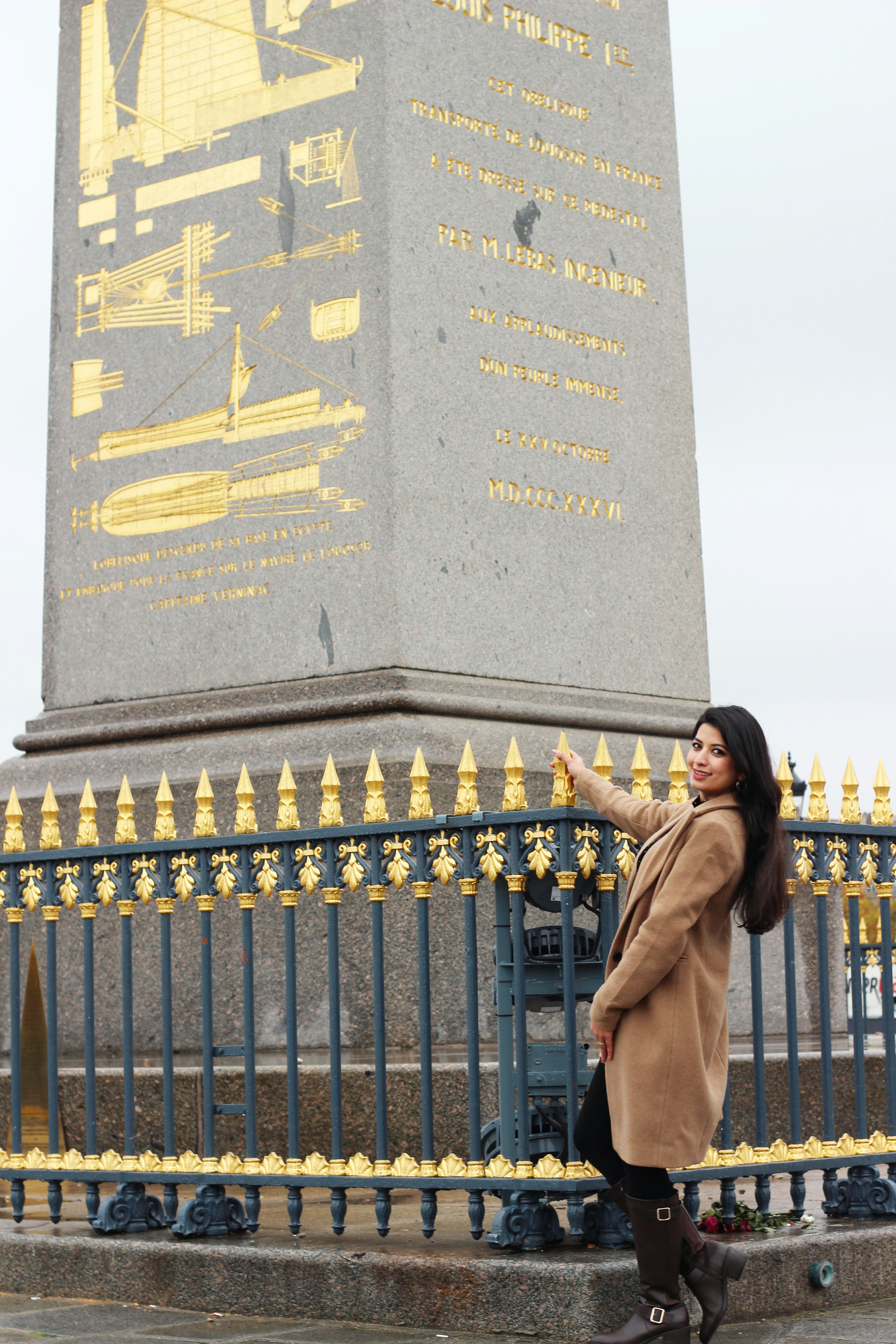 Girl in Camel Coat by the Monument's Gold-Kated Fence
