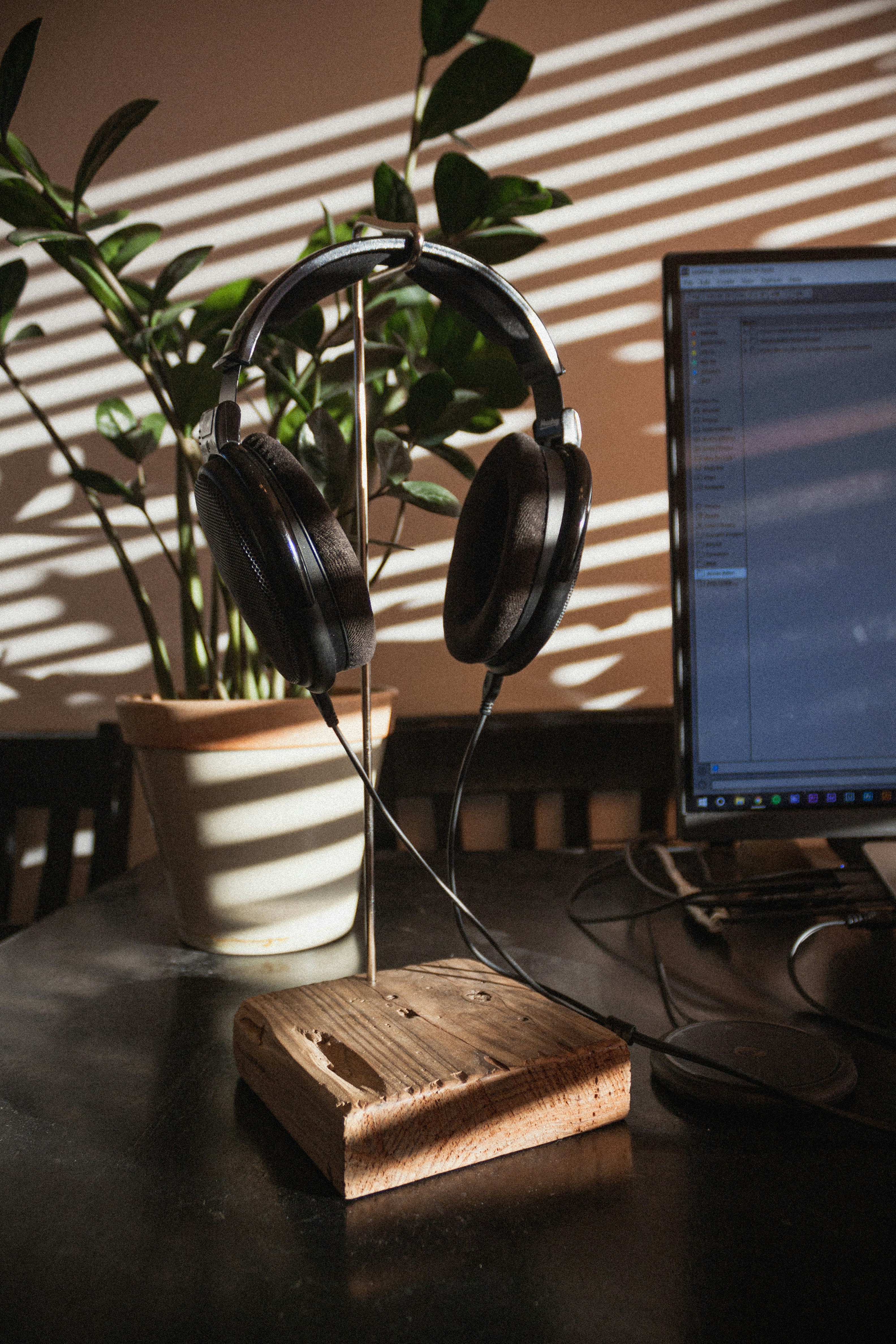 Headphones on a rustic stand beside a monitor and plant