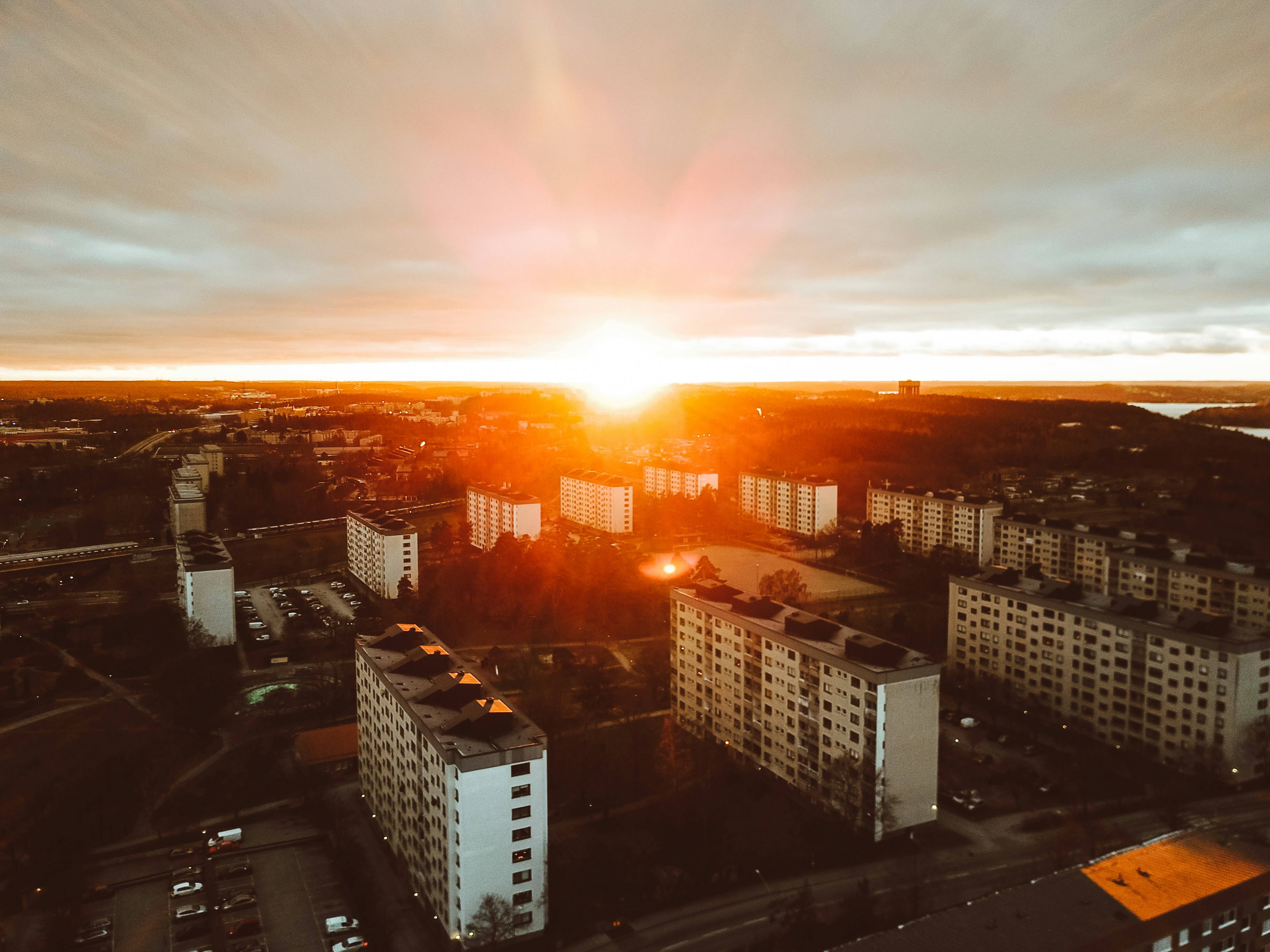Sunrise illuminating apartment buildings with a warm glow, under a cloudy sky.