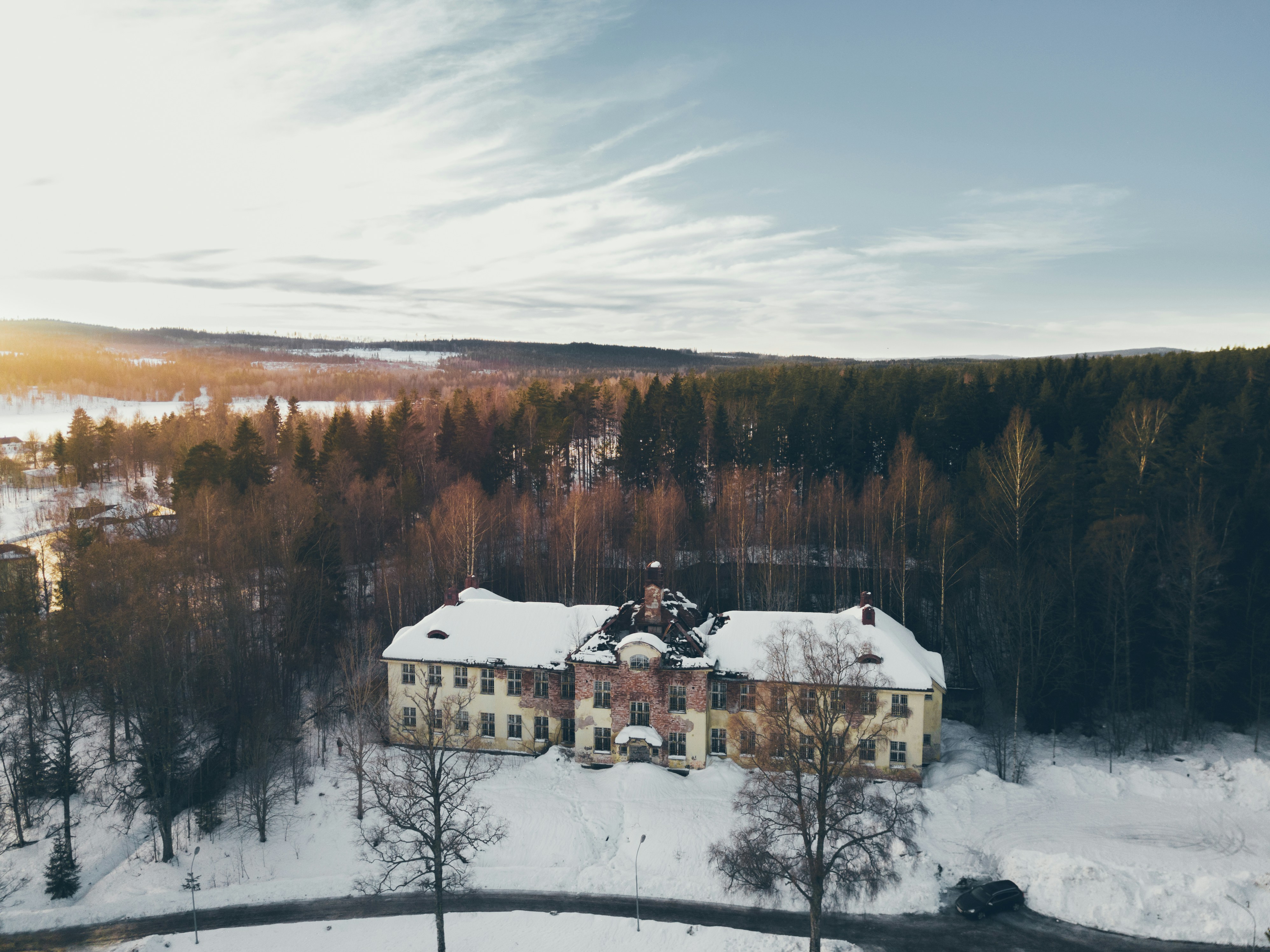 House and field covered with snow surrounded with green trees under ...