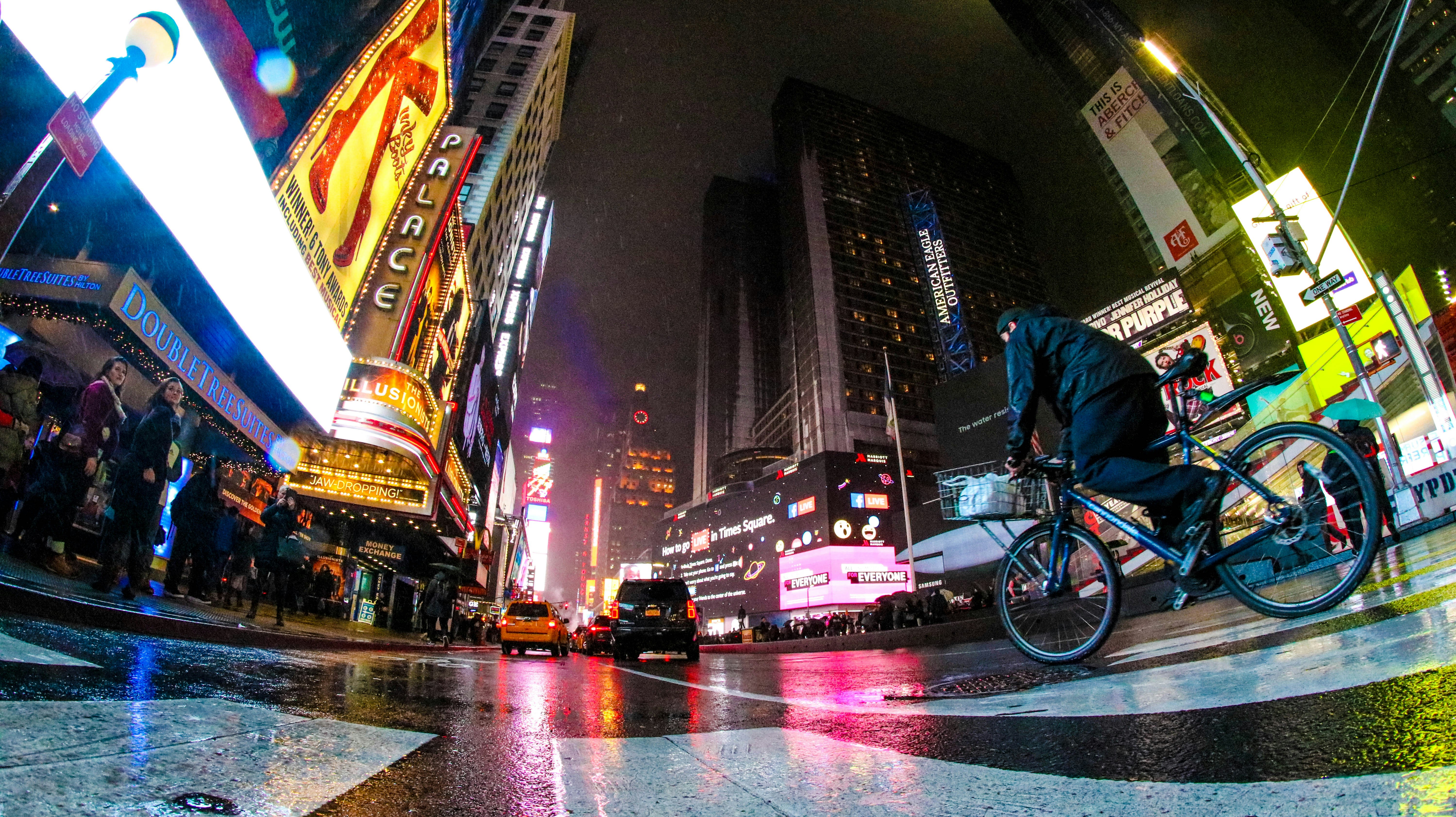 Low-Angle Neon Crossing: Cyclist in a Rain-Slick Night