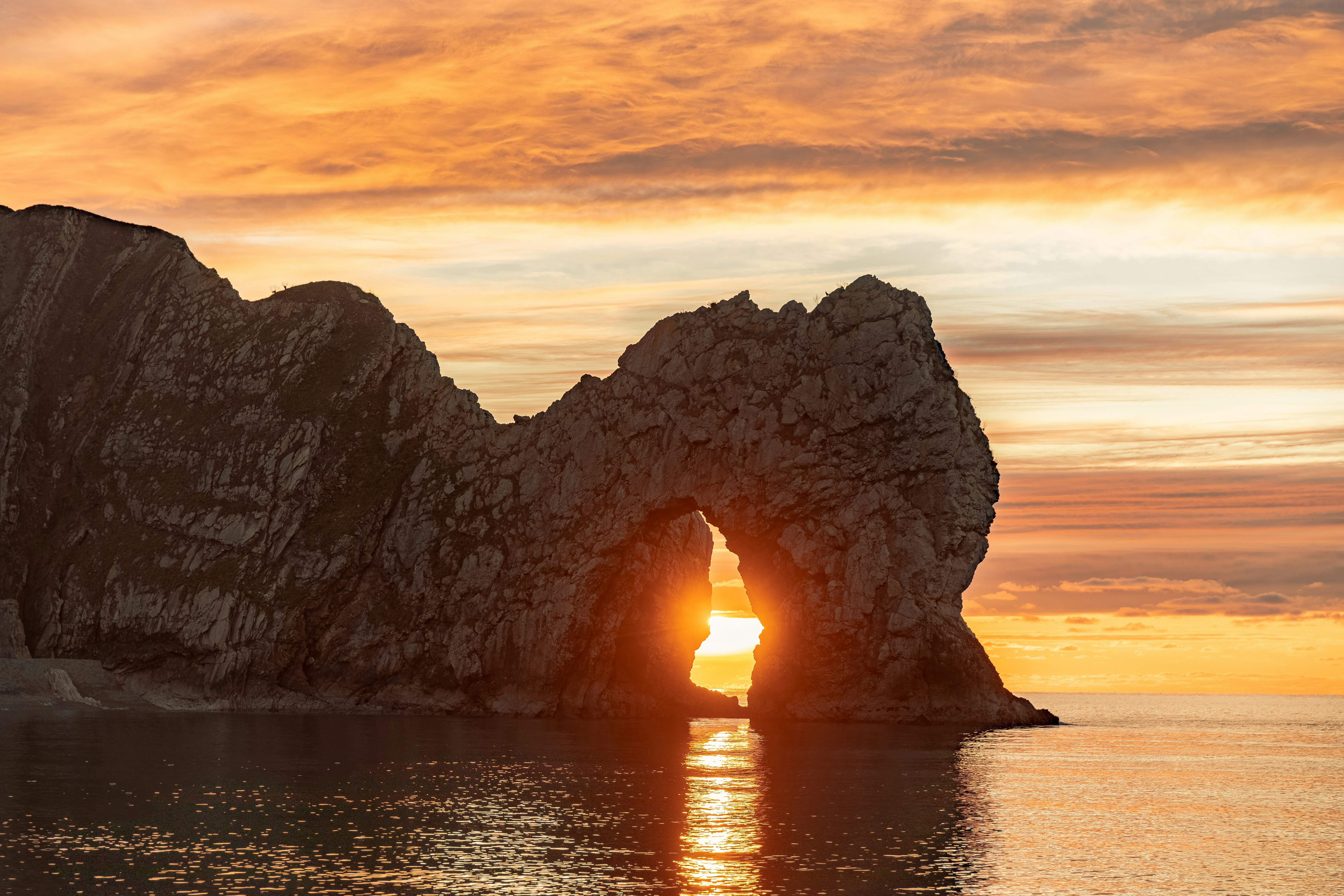 The Sunlit Arch: A Golden Crest Between Sea and Sky