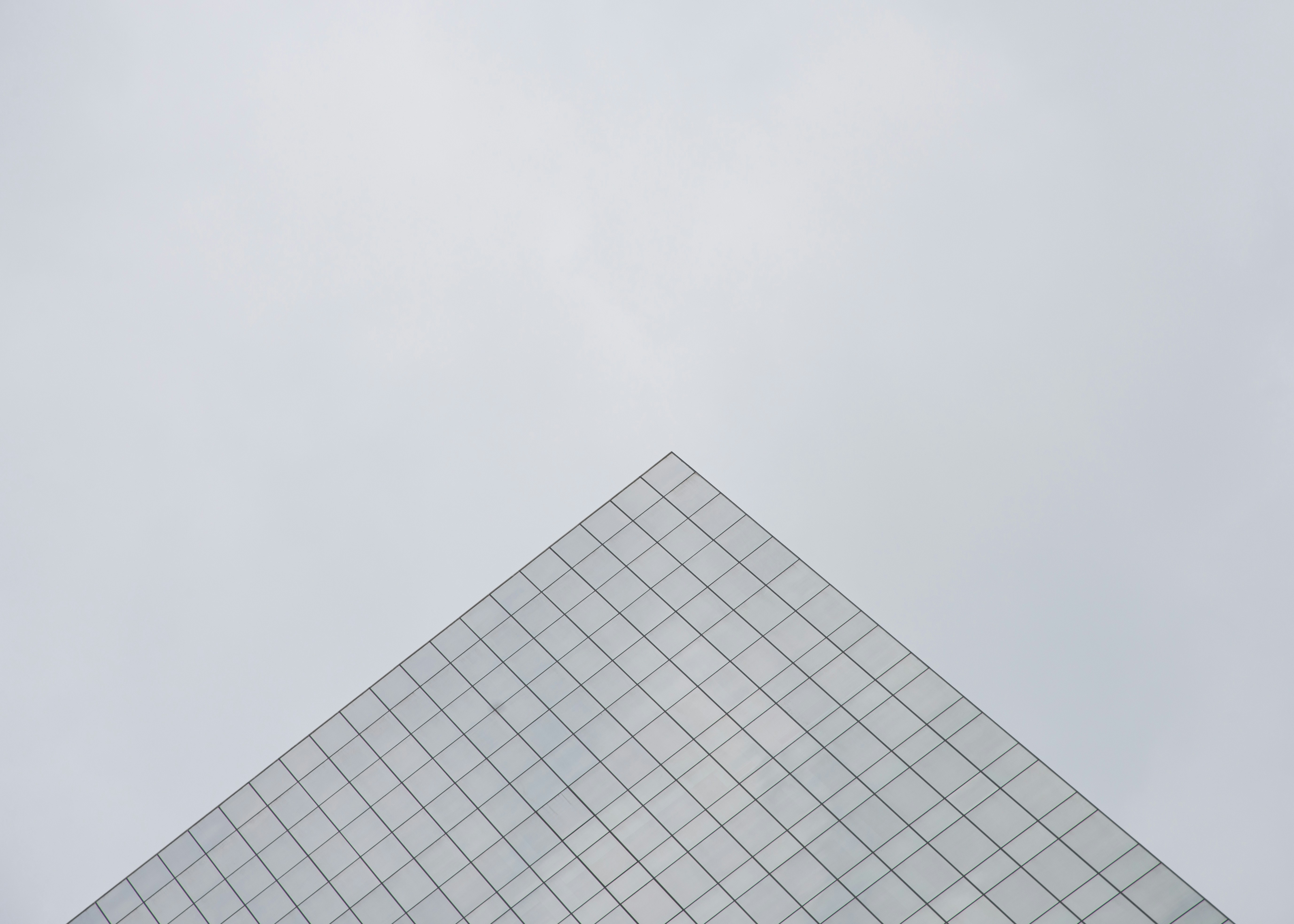 A sleek glass pyramid structure emerges against a muted sky, emphasizing modern architectural design.