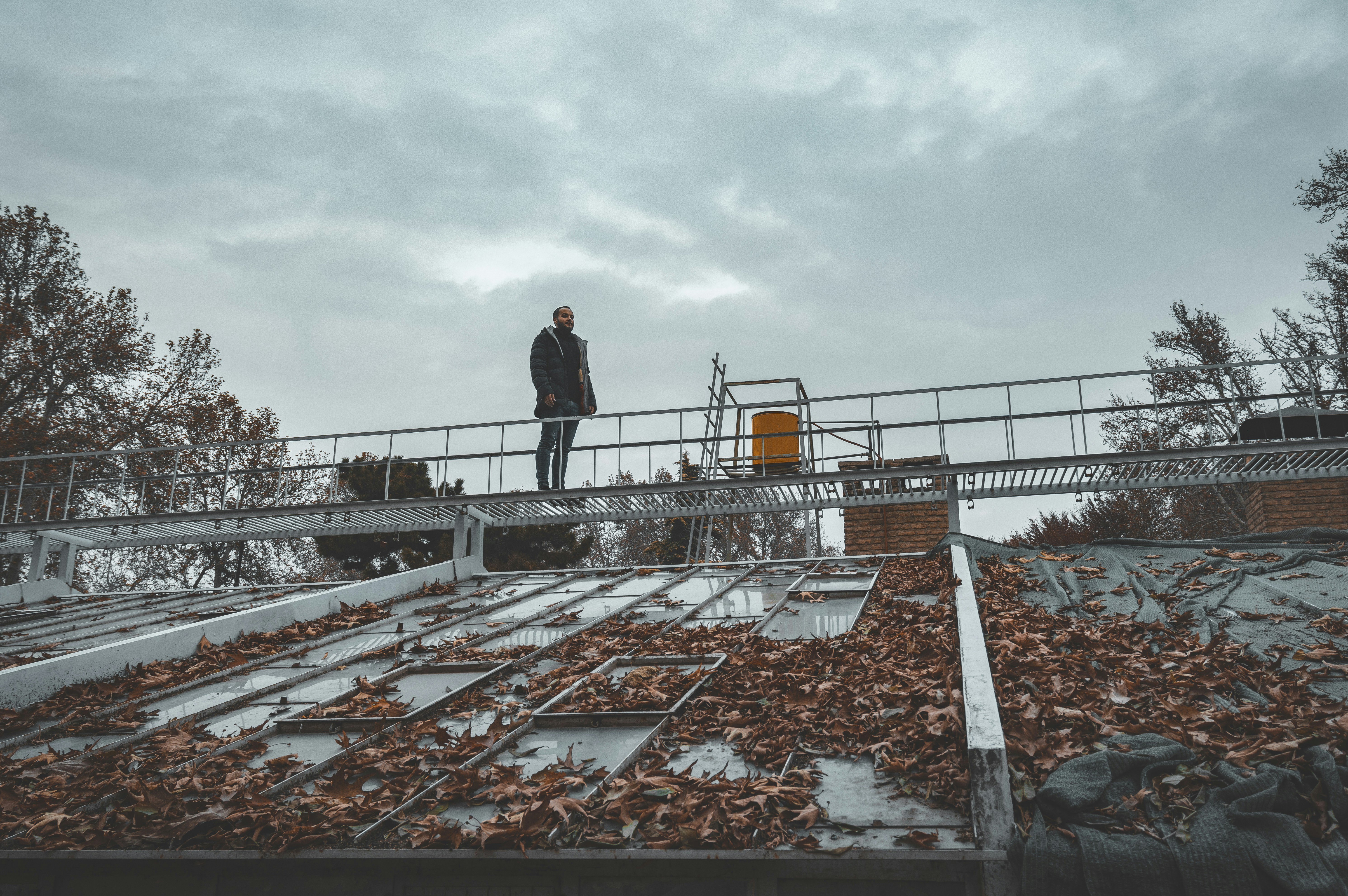 Lone Figure on a Weathered Rooftop Walkway Beneath a Clouded Sky