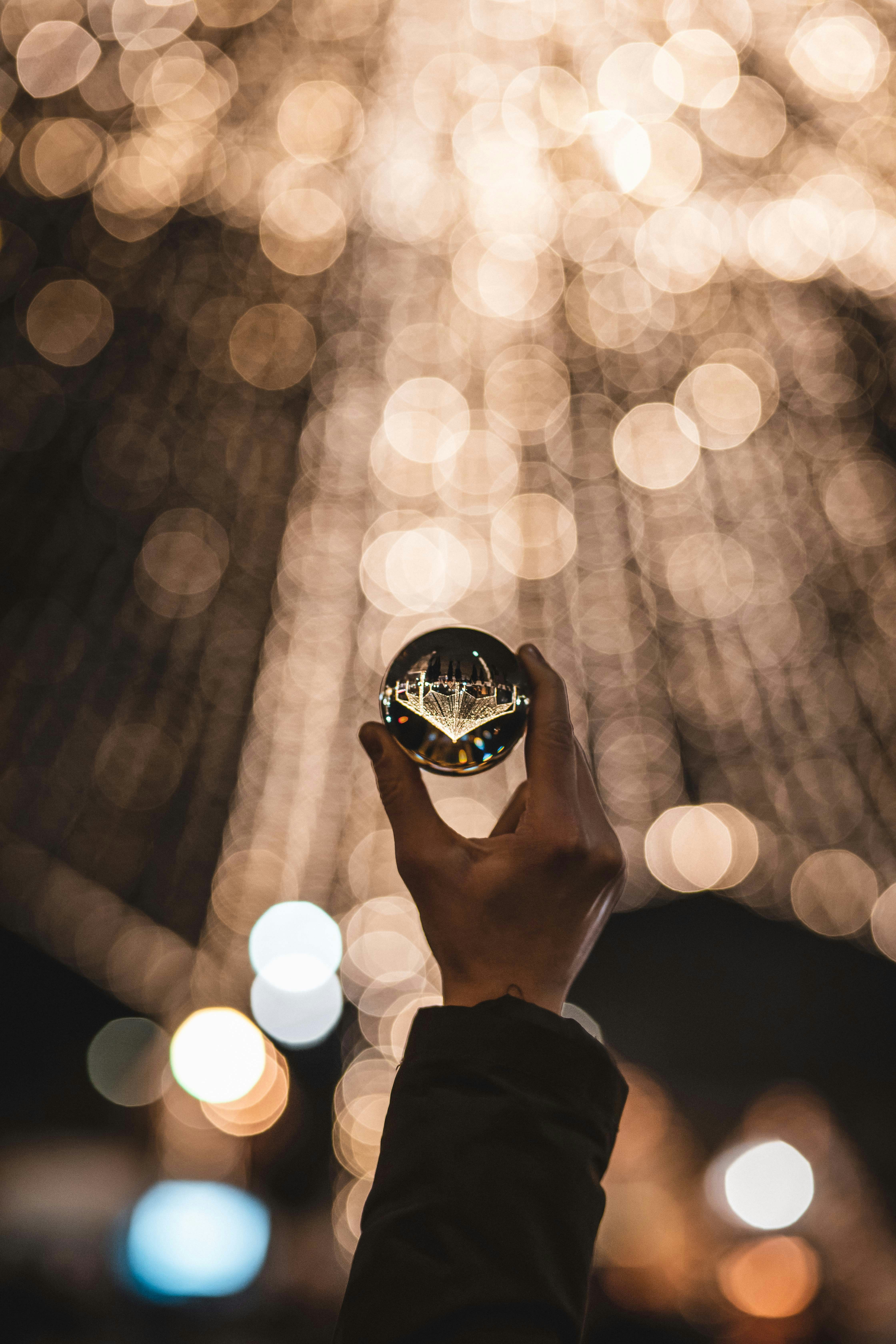 Hand-Held Crystal Ball Reflects a City of Light Through Golden Bokeh