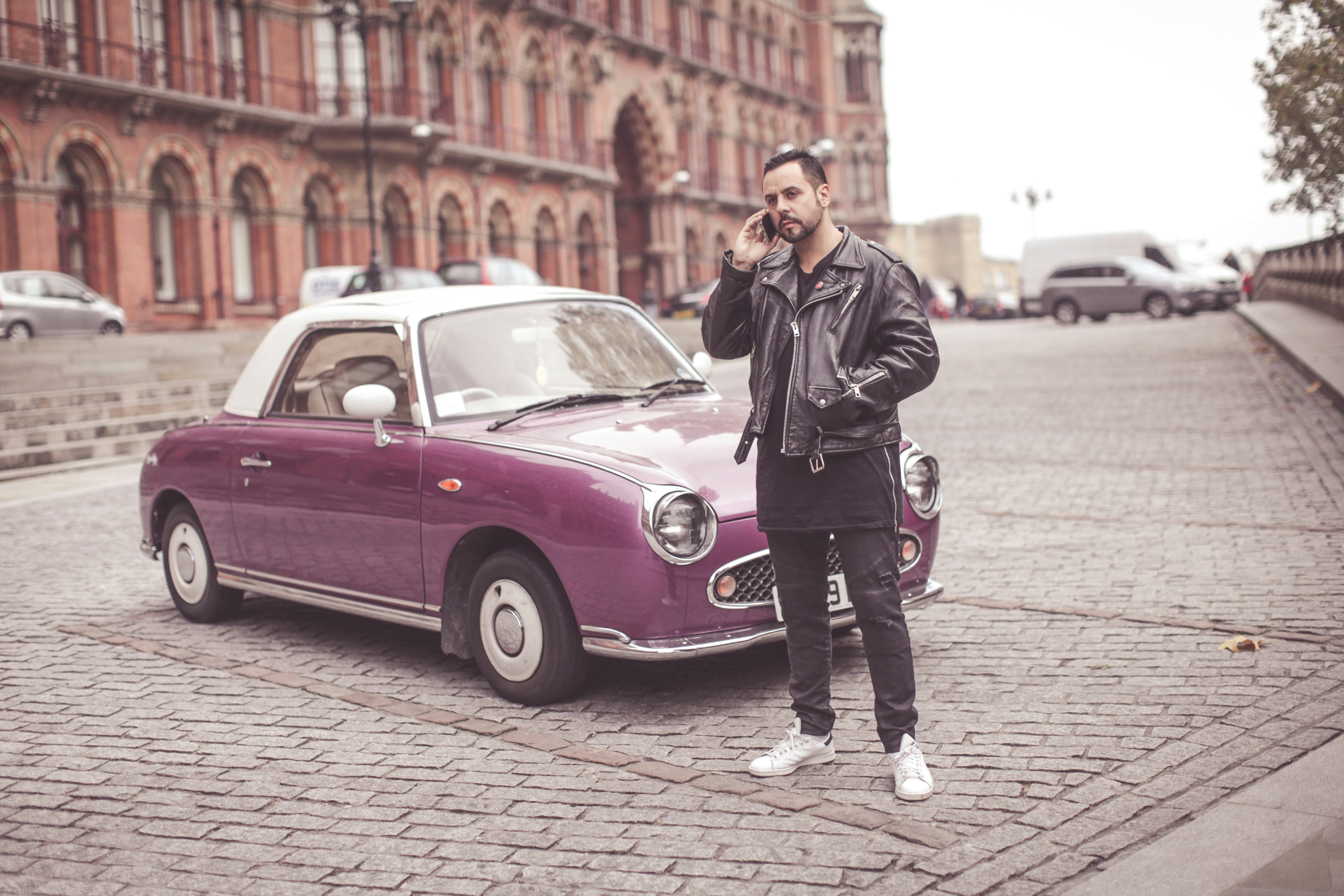 man standing near car beside building
