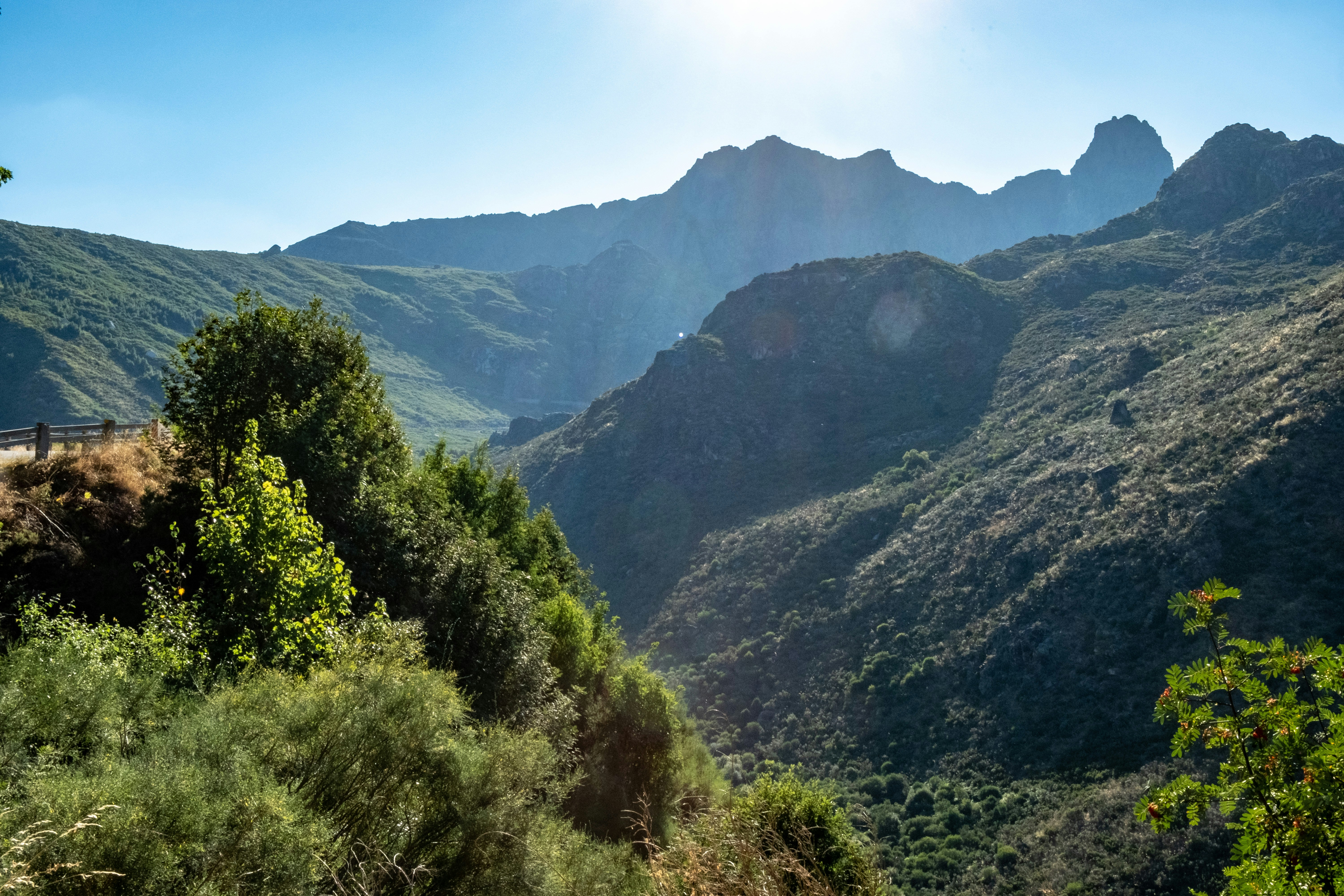 Lush green valleys and rugged mountains under a bright sky.