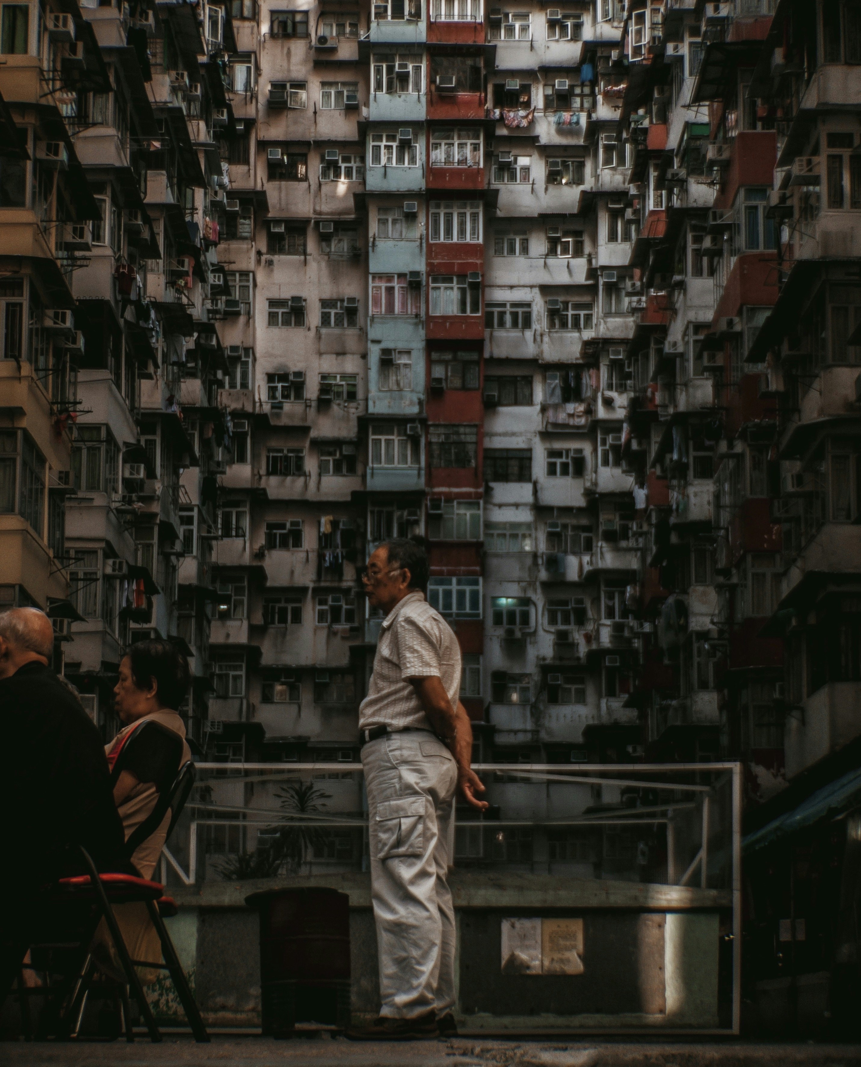 Man standing in front of densely packed high-rise apartments, capturing the complexity of urban living.