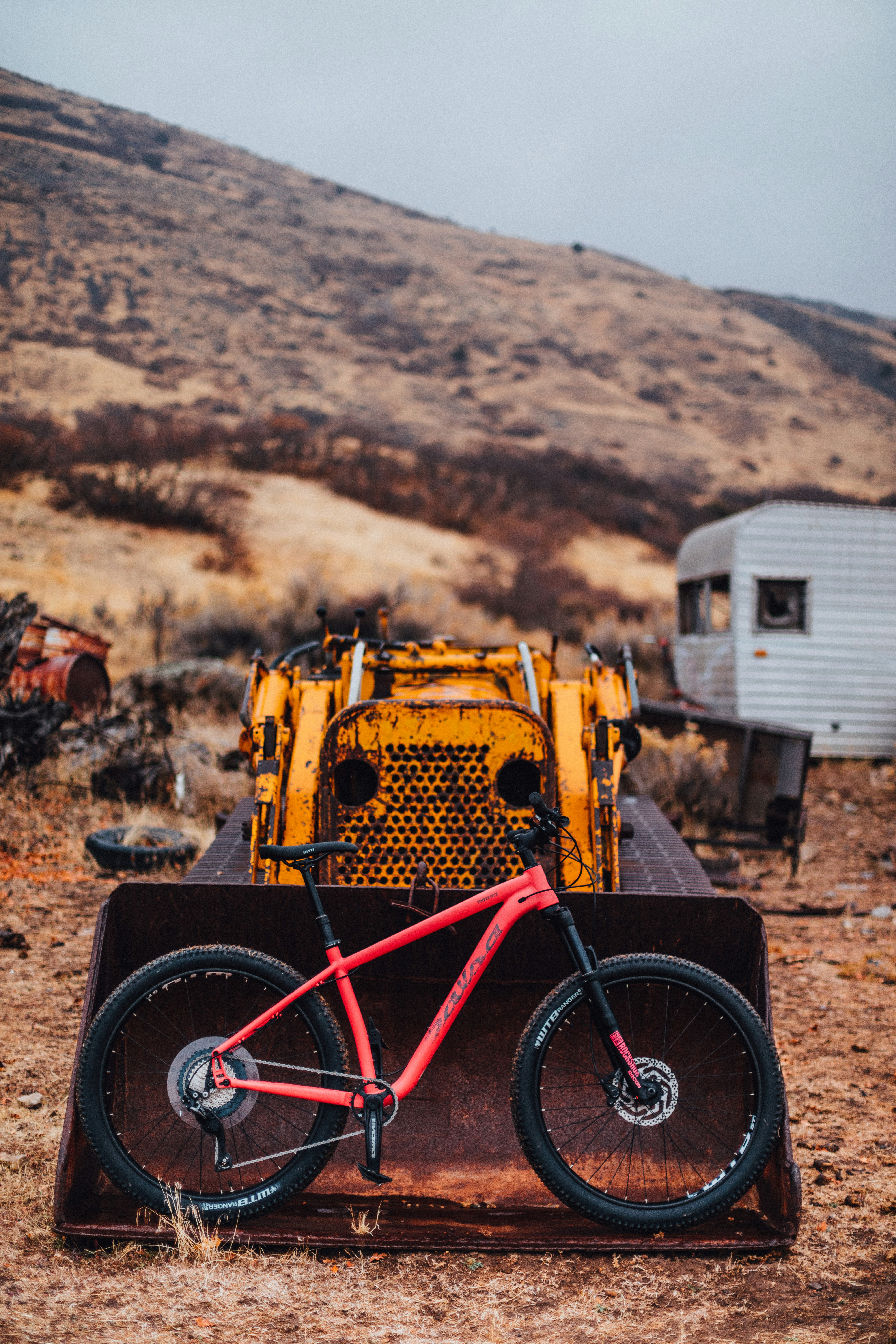 Crimson Mountain Bike Resting on a Rusty Bulldozer in a Mojave Junkyard