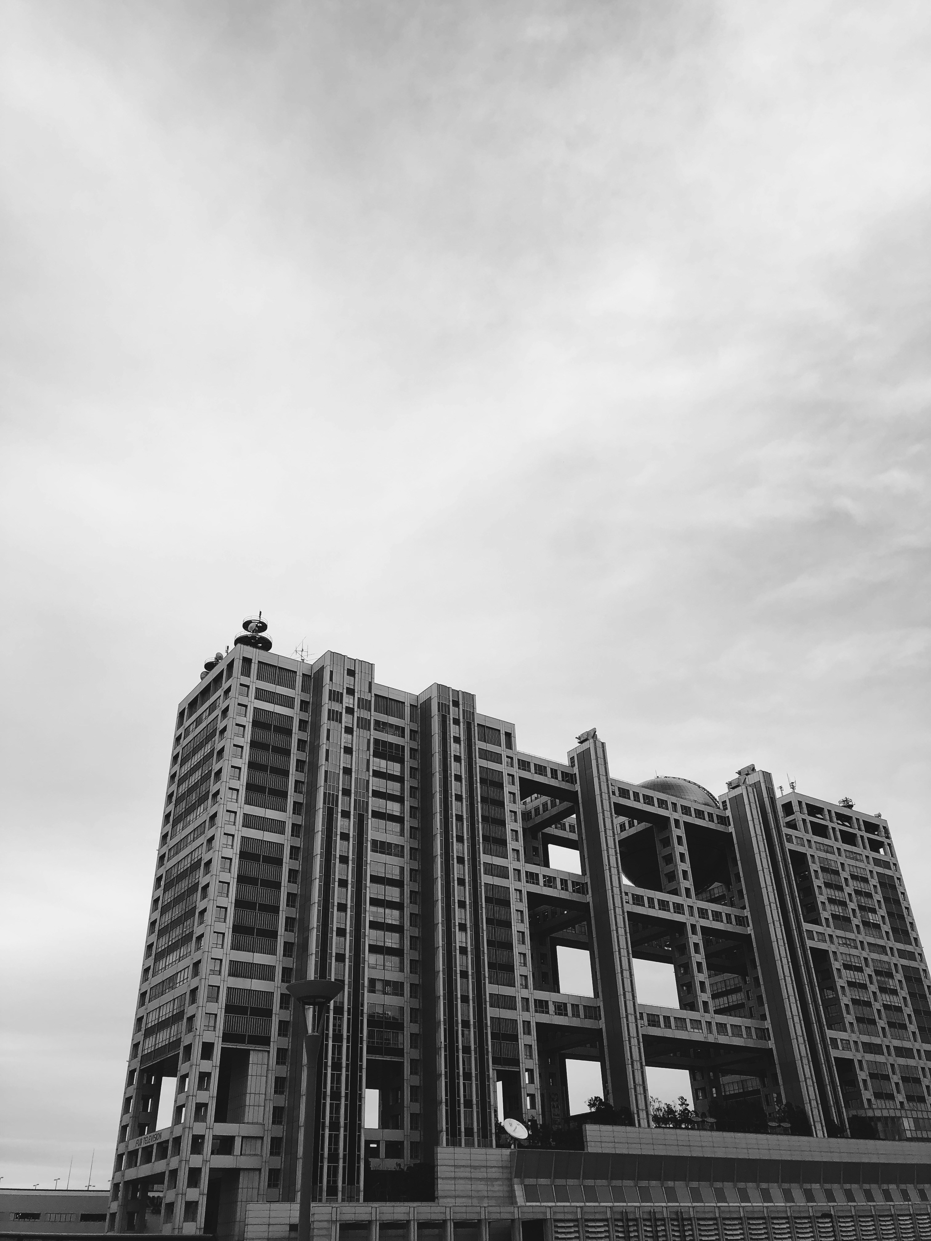 Modern high-rise building with distinctive geometric openings and a cloudy sky backdrop.