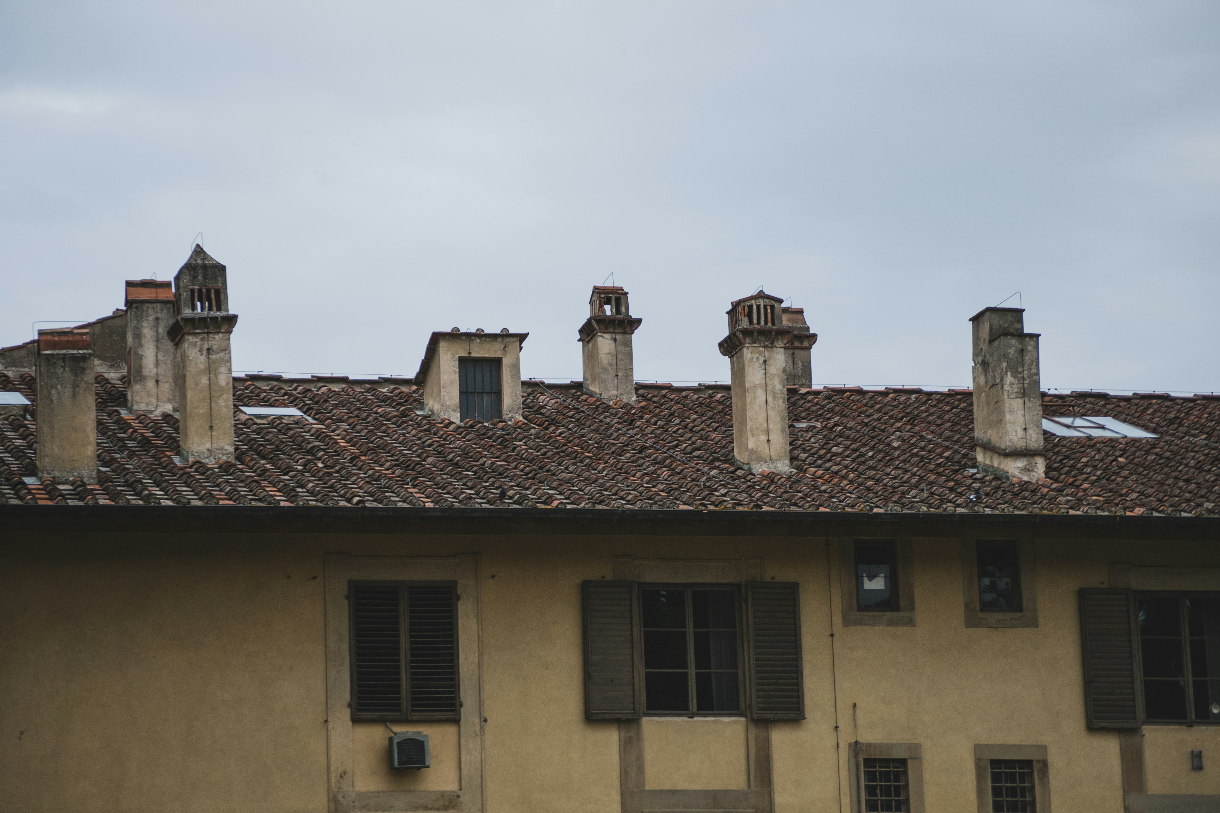 Historic rooftops adorned with chimneys and textured tiles, showcasing the architectural charm of a Florentine building.