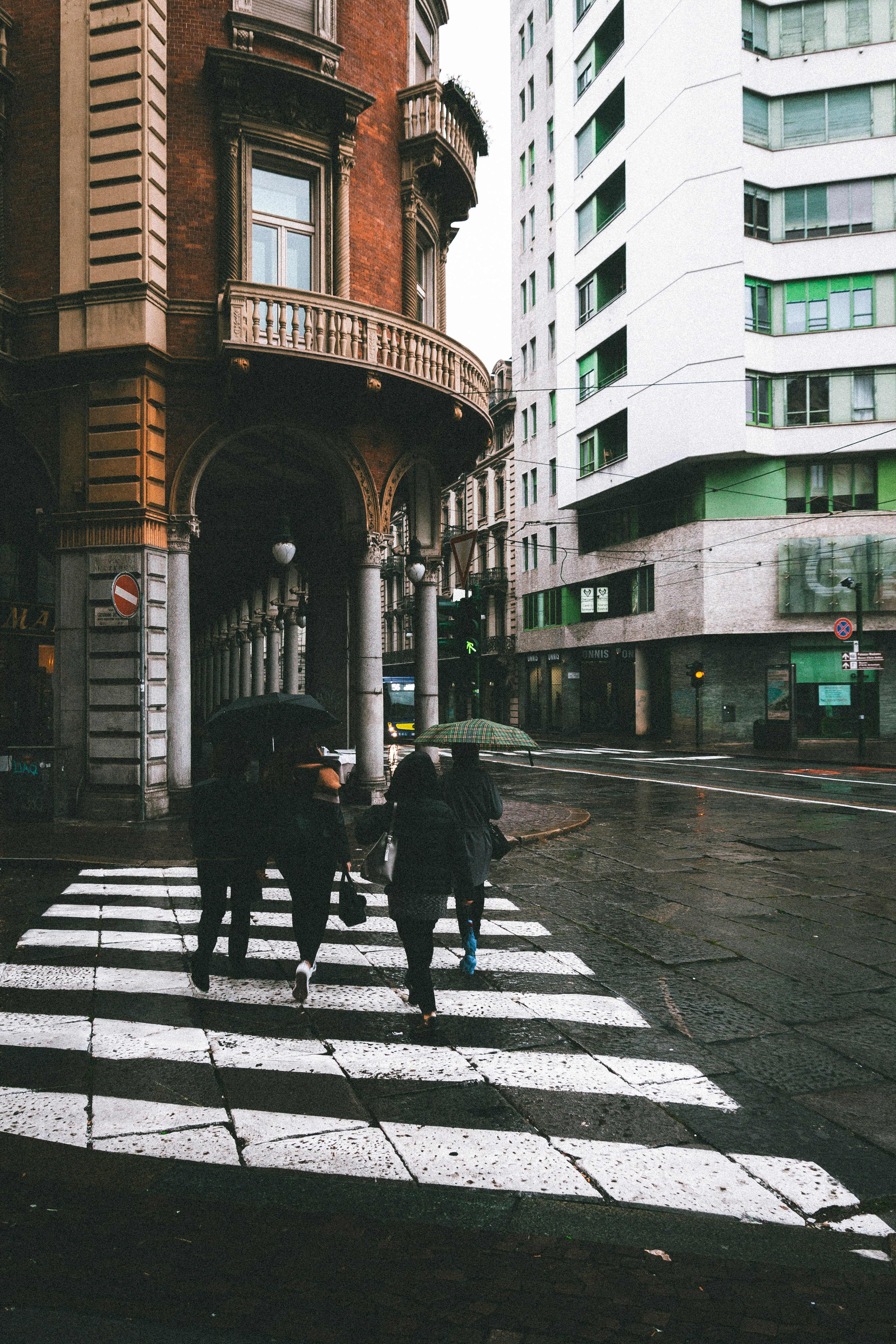 Crossing in the Rain: Umbrellas Under Arches and Glass Facades