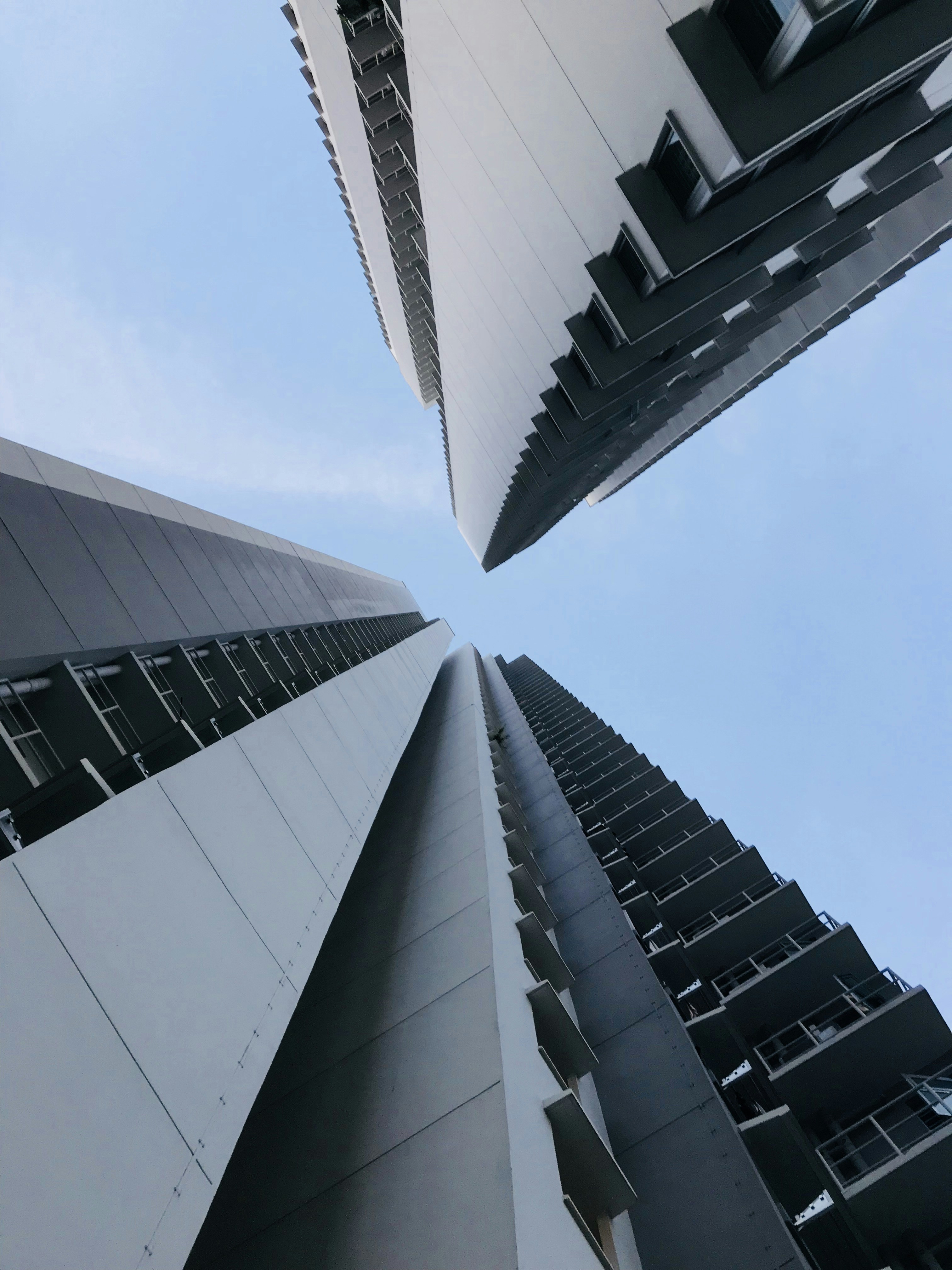 Looking up at the sharp angles of towering buildings against a clear blue sky.