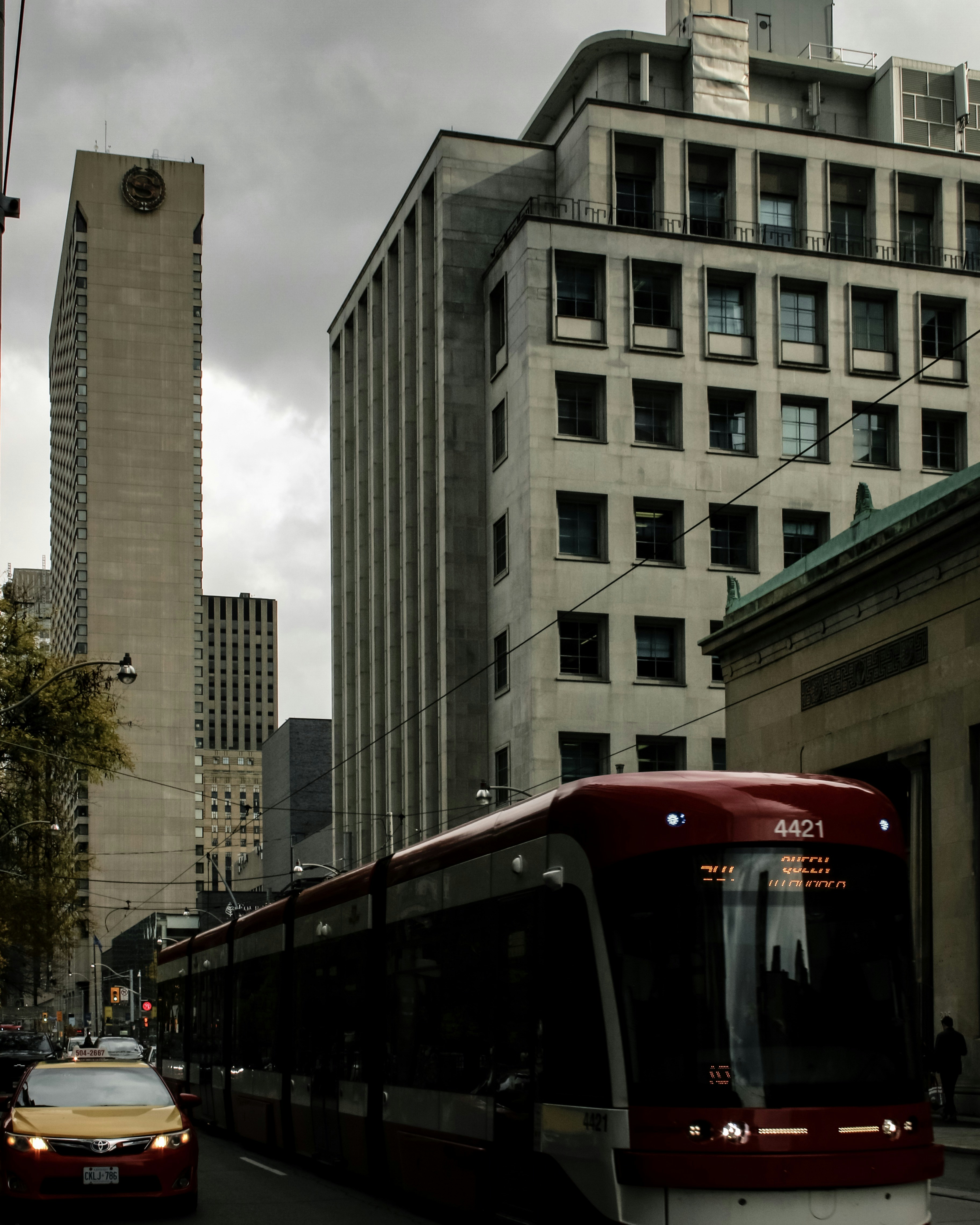 Red streetcar threading the gray canyon of downtown towers