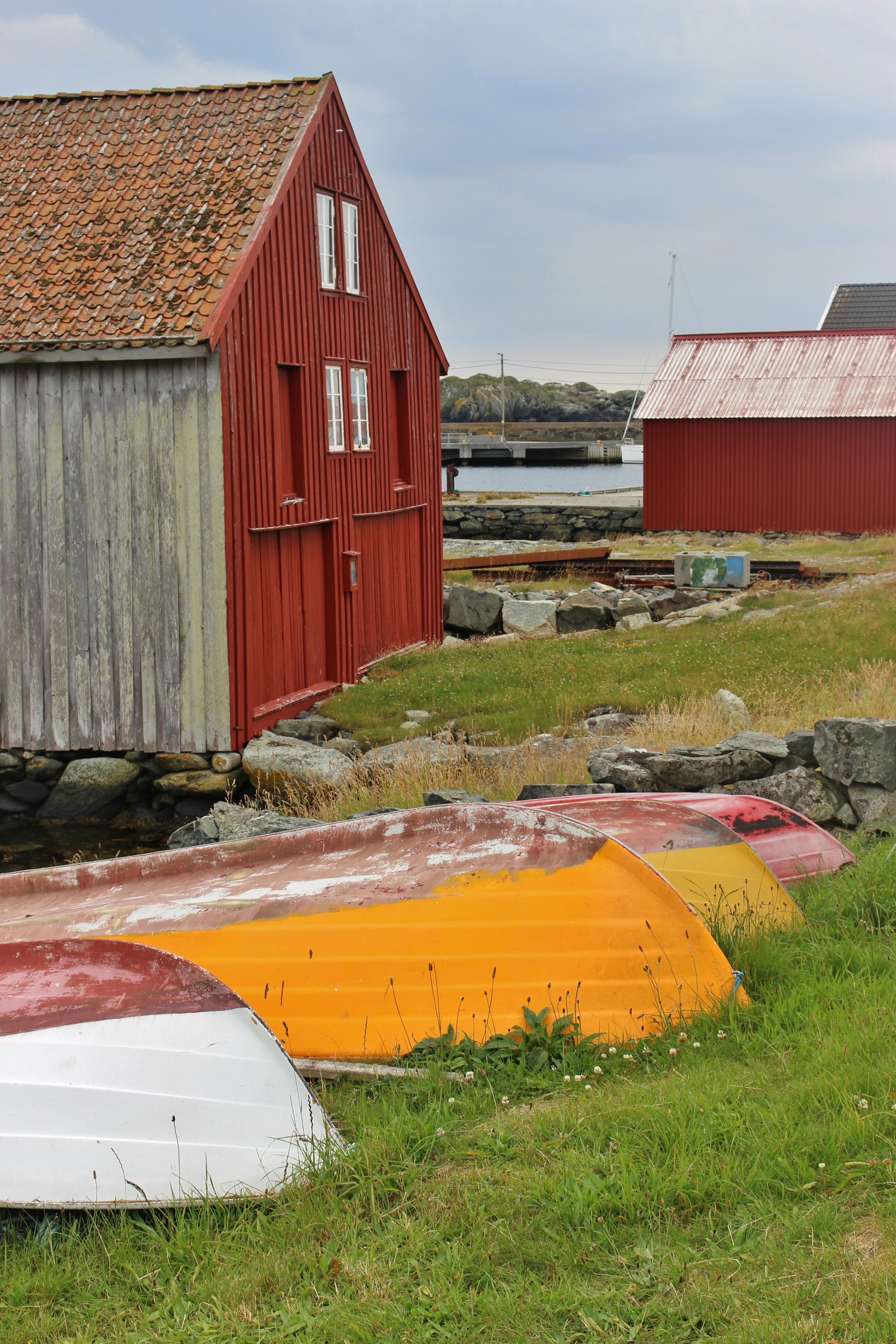 Red Wharf House by a Quiet Harbor, Framed by Painted Hulls