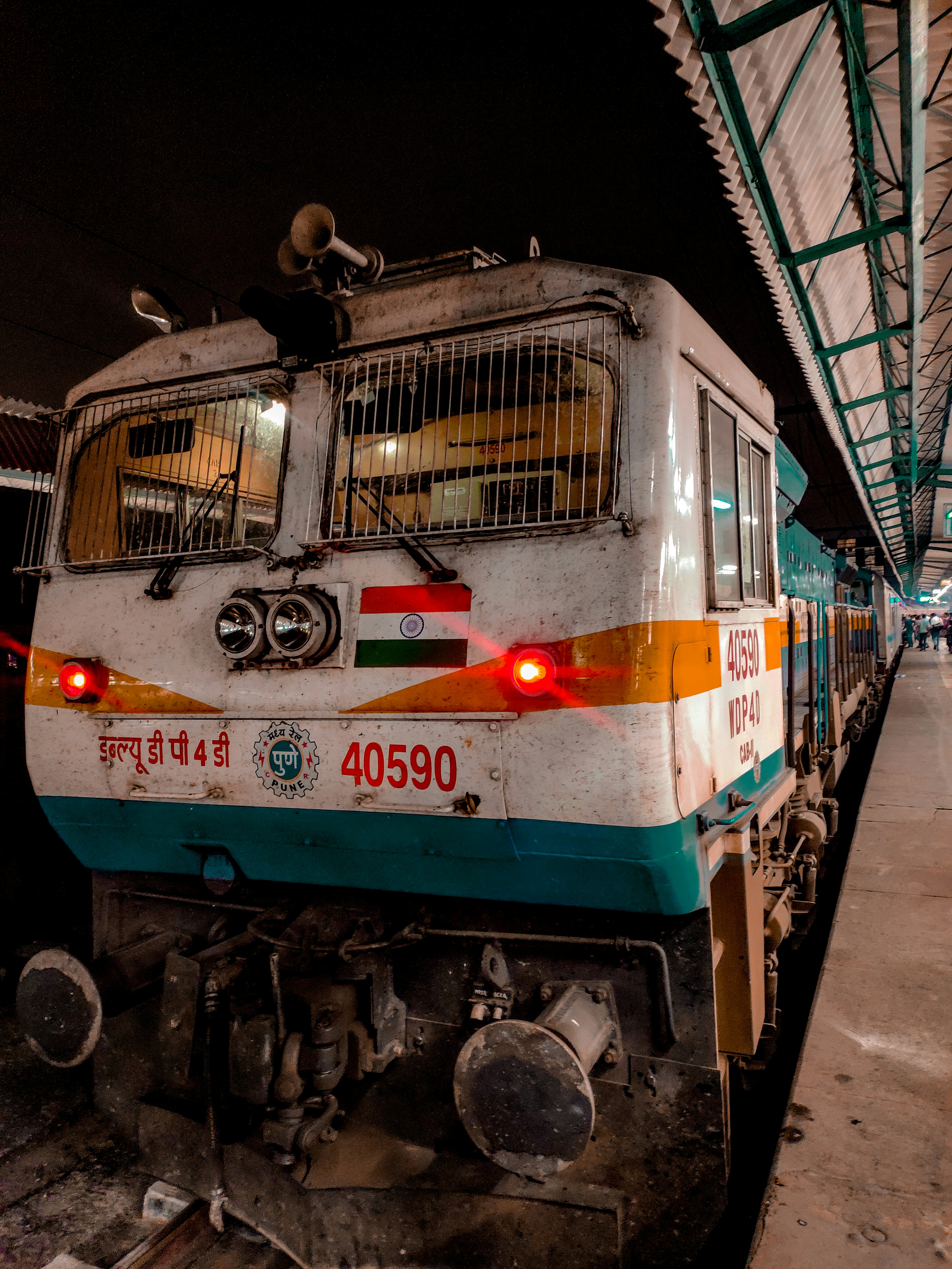 A close-up view of a train at a station, showcasing intricate details of its design and the surrounding infrastructure. The train's number and Indian flag are prominently displayed.