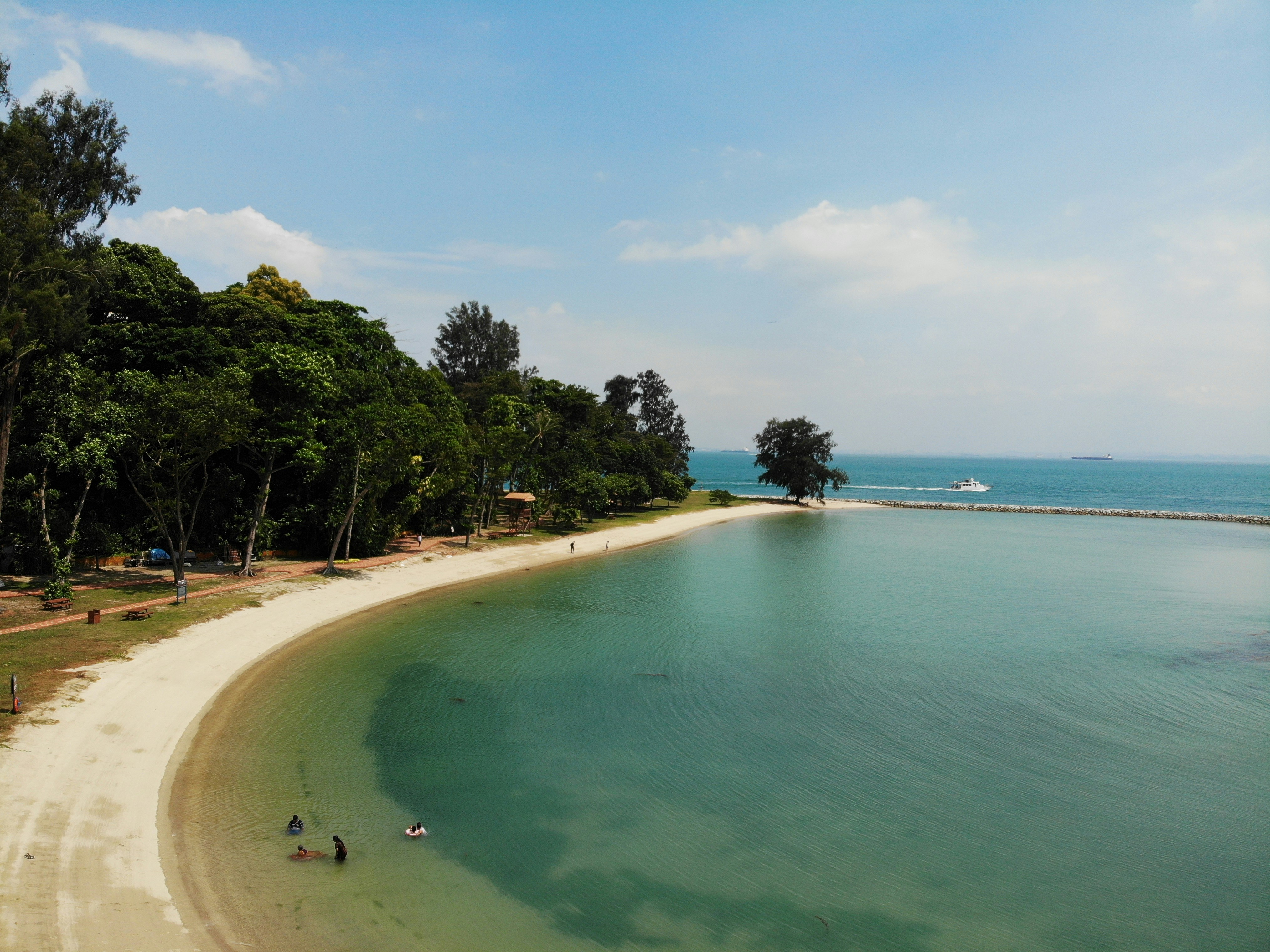 A tranquil beach on Kusu Island with clear blue waters and lush greenery under a bright sky.