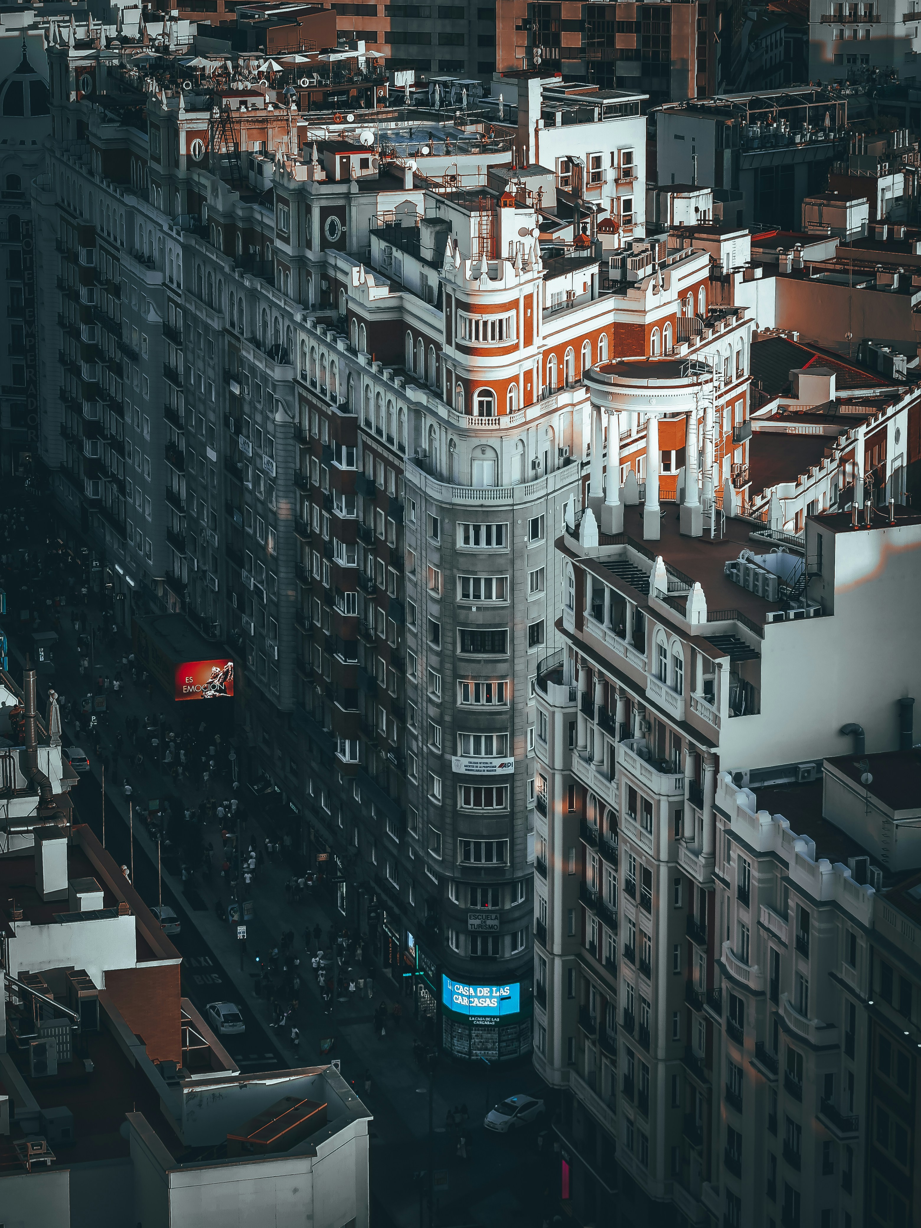 Aerial view of intricate urban architecture with vibrant signage, showcasing the dynamic interplay of light and shadow across the buildings.