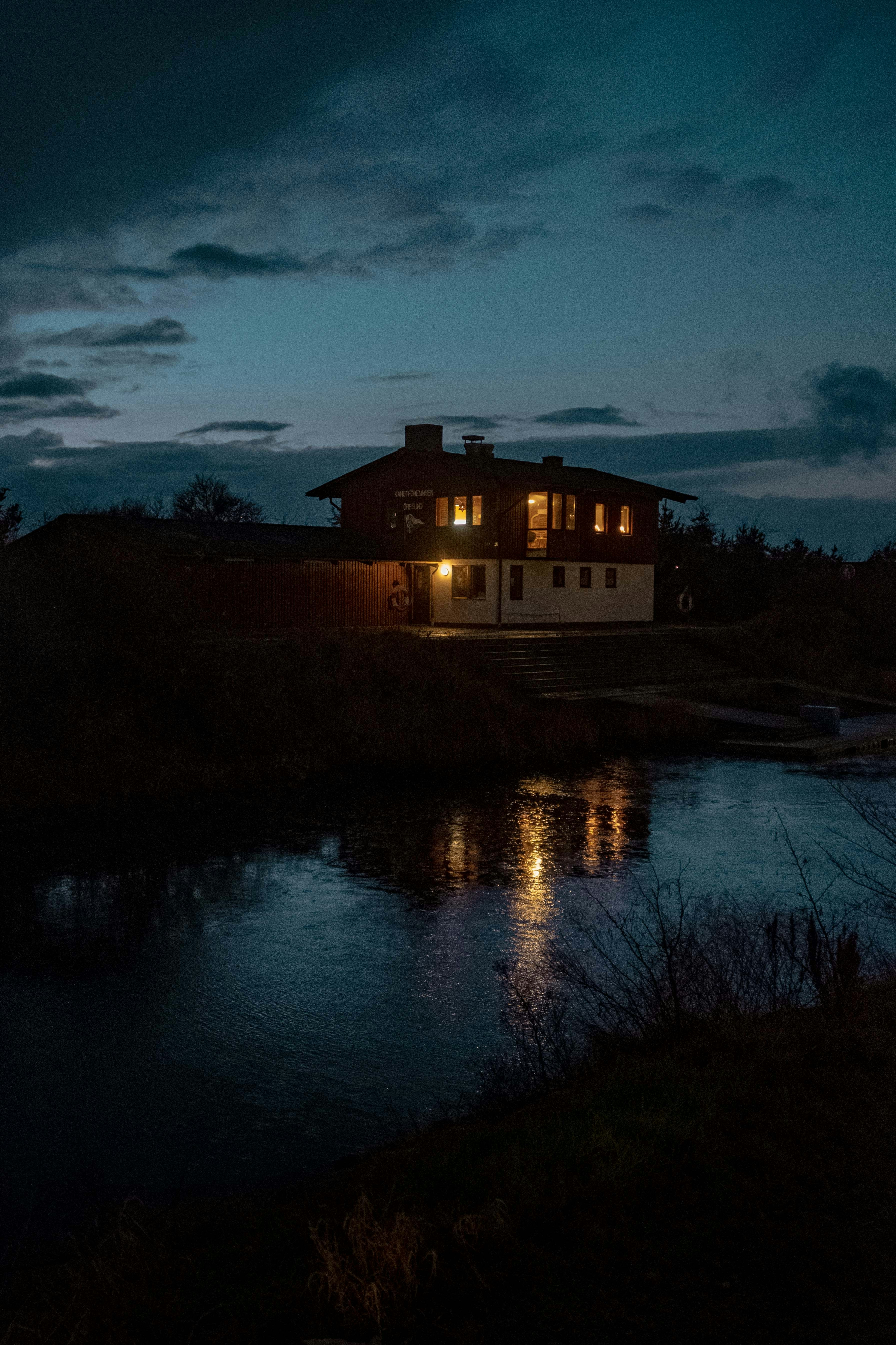 Dusk House by the River: Warm Windows Reflect a Quiet Night