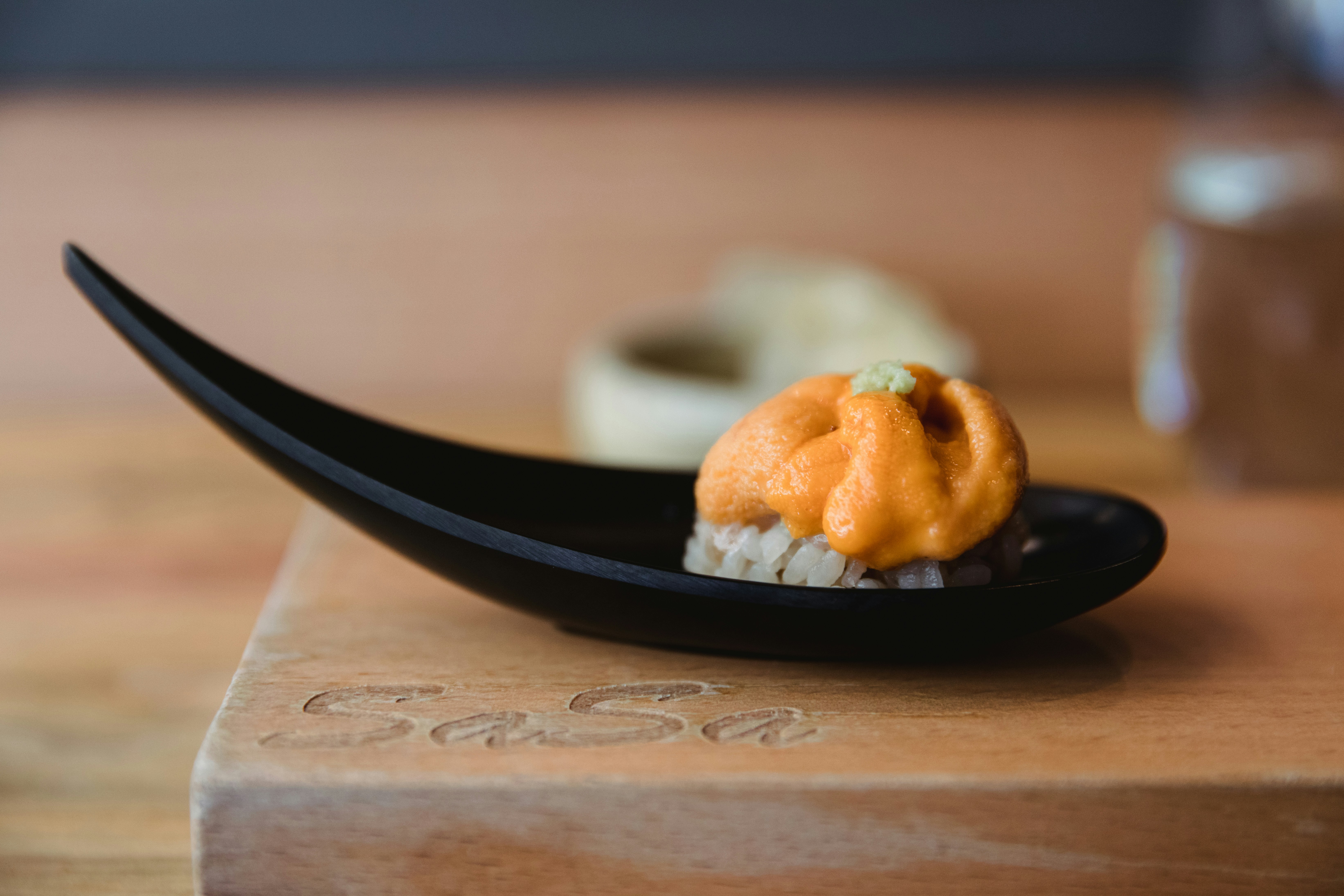 Nigiri on a Sleek Black Spoon: A Minimal Moment on Warm Wood