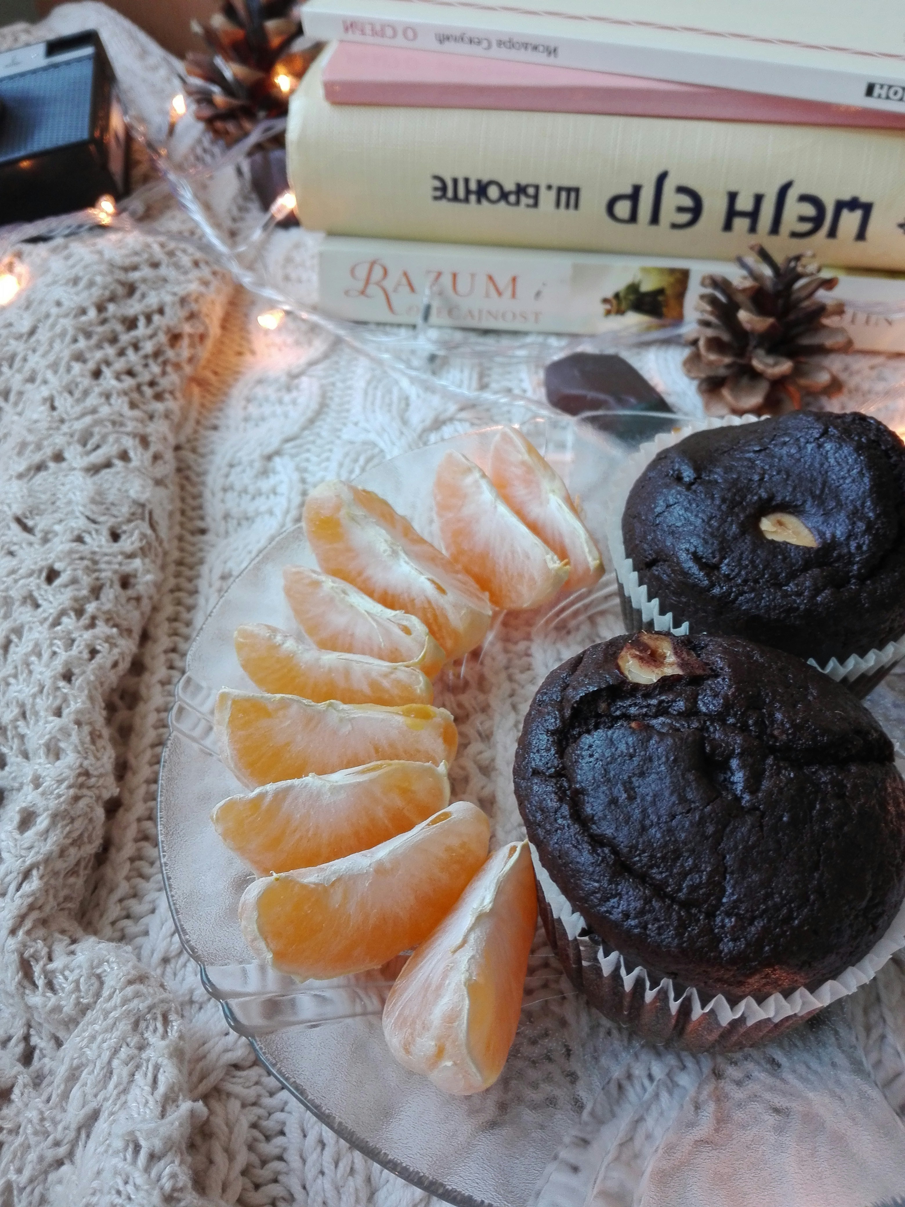 A plate of chocolate muffins accompanied by fresh orange segments, set against a backdrop of soft textures and warm lighting.