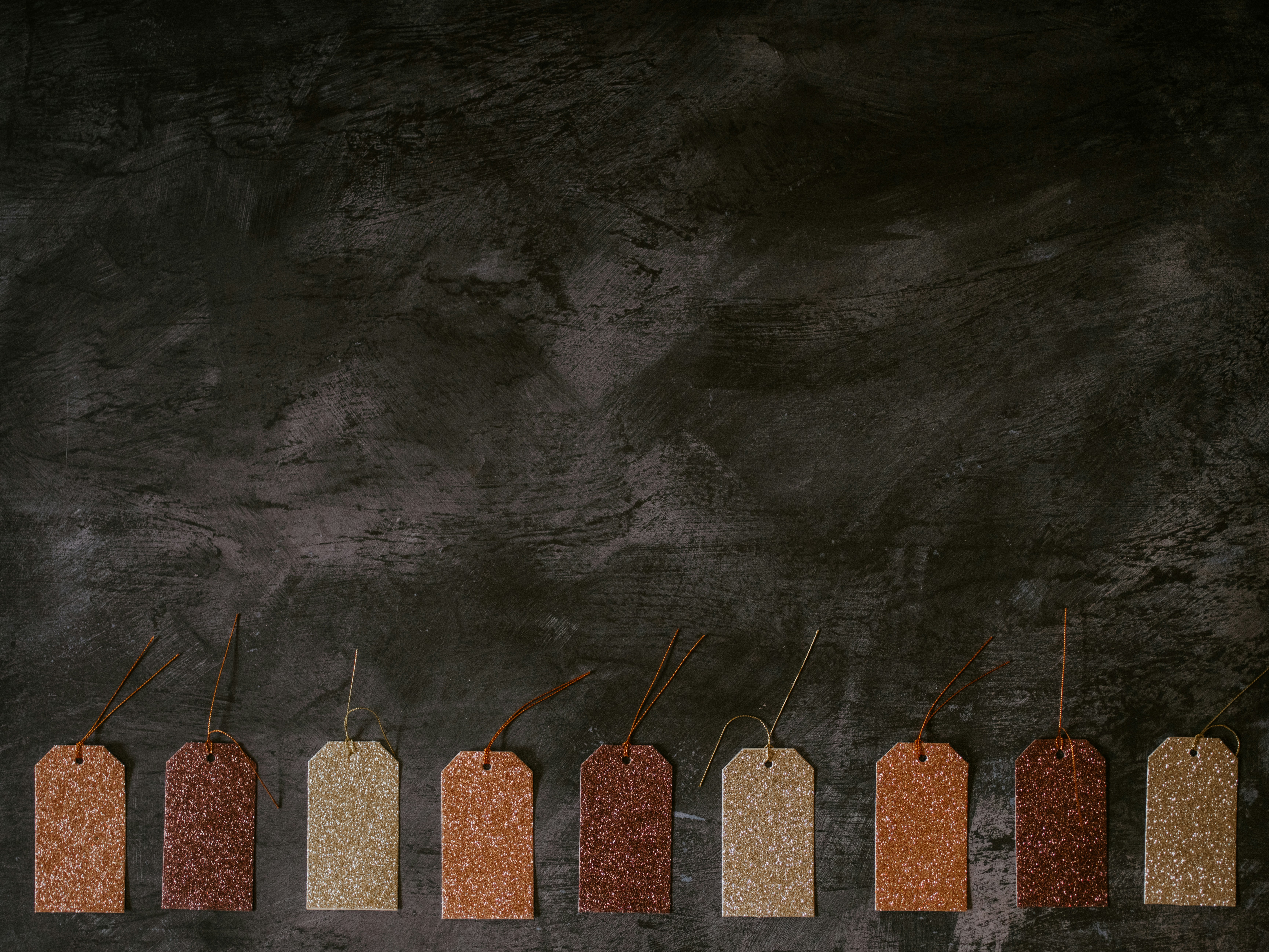 A series of textured tags arranged in a line against a dark, textured background, showcasing varying shades of brown and gold.