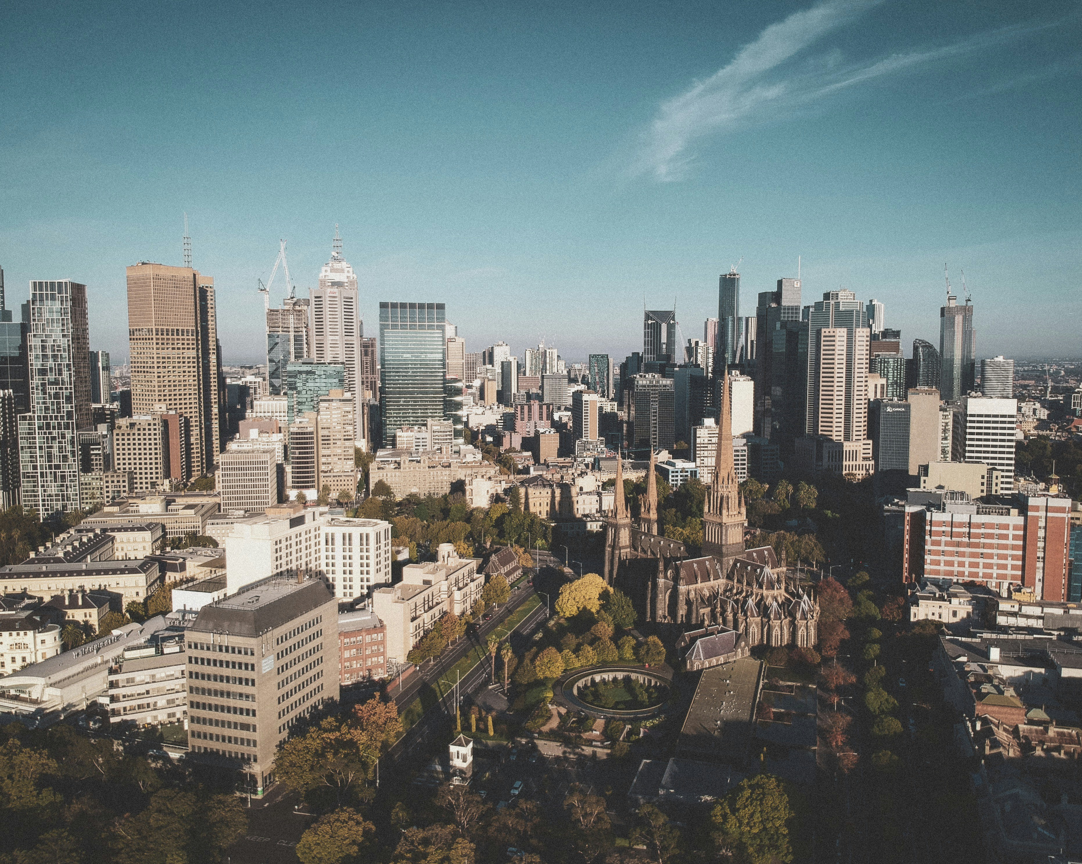 Aerial view of a sprawling urban skyline with diverse high-rise architecture under a clear sky.