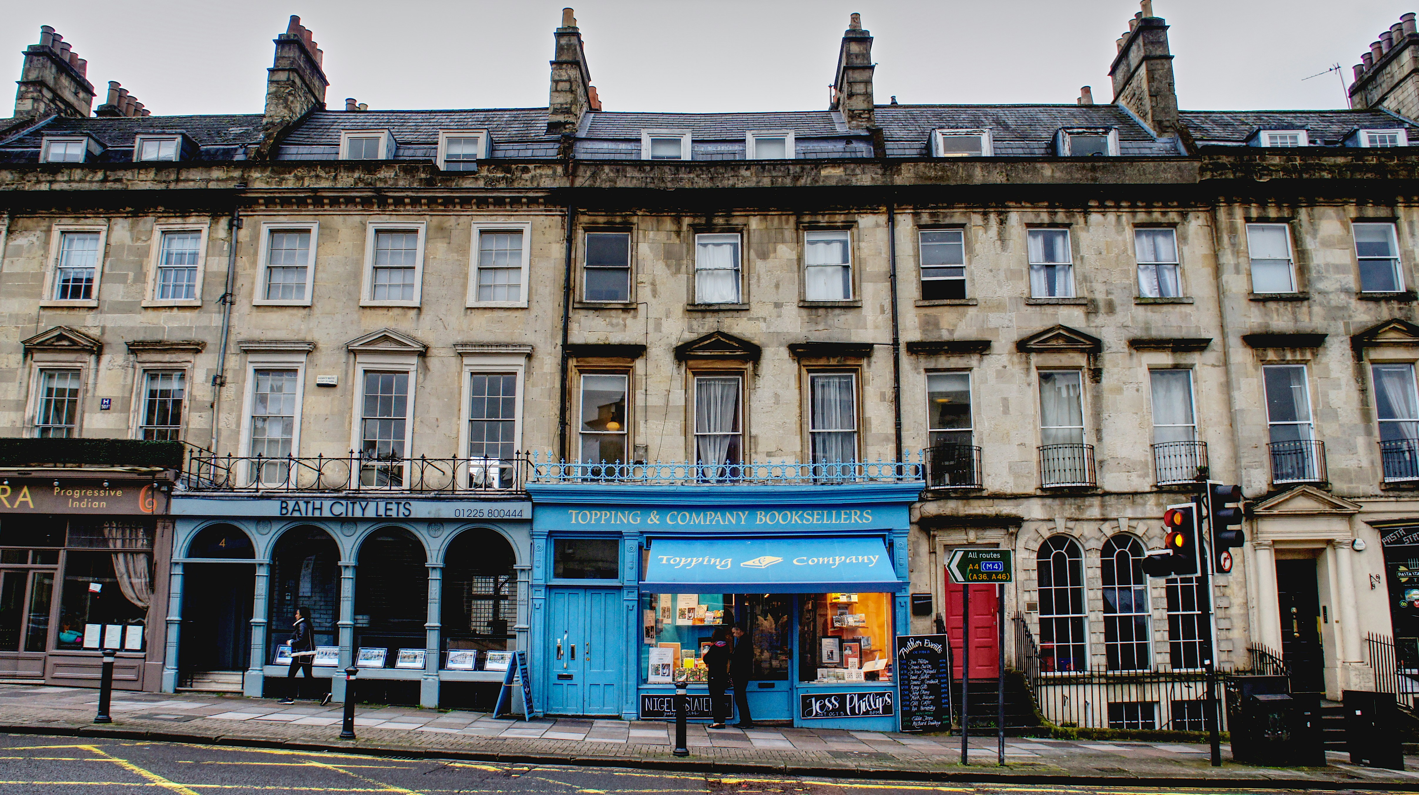 Row of historic buildings with a bright blue storefront in Bath.