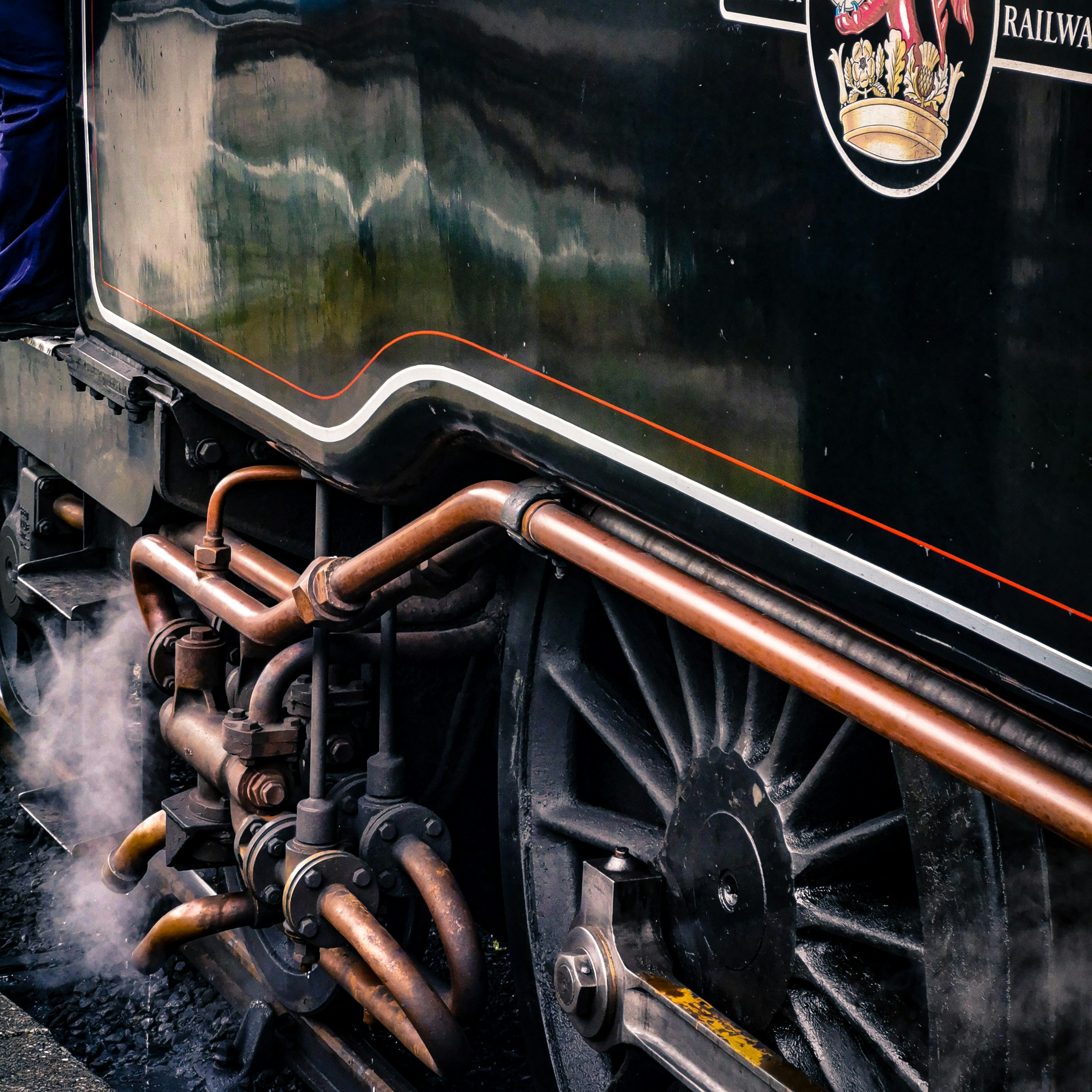 Close-up of a vintage steam locomotive showcasing intricate mechanical details and steam emissions. The image highlights the craftsmanship of railway engineering.