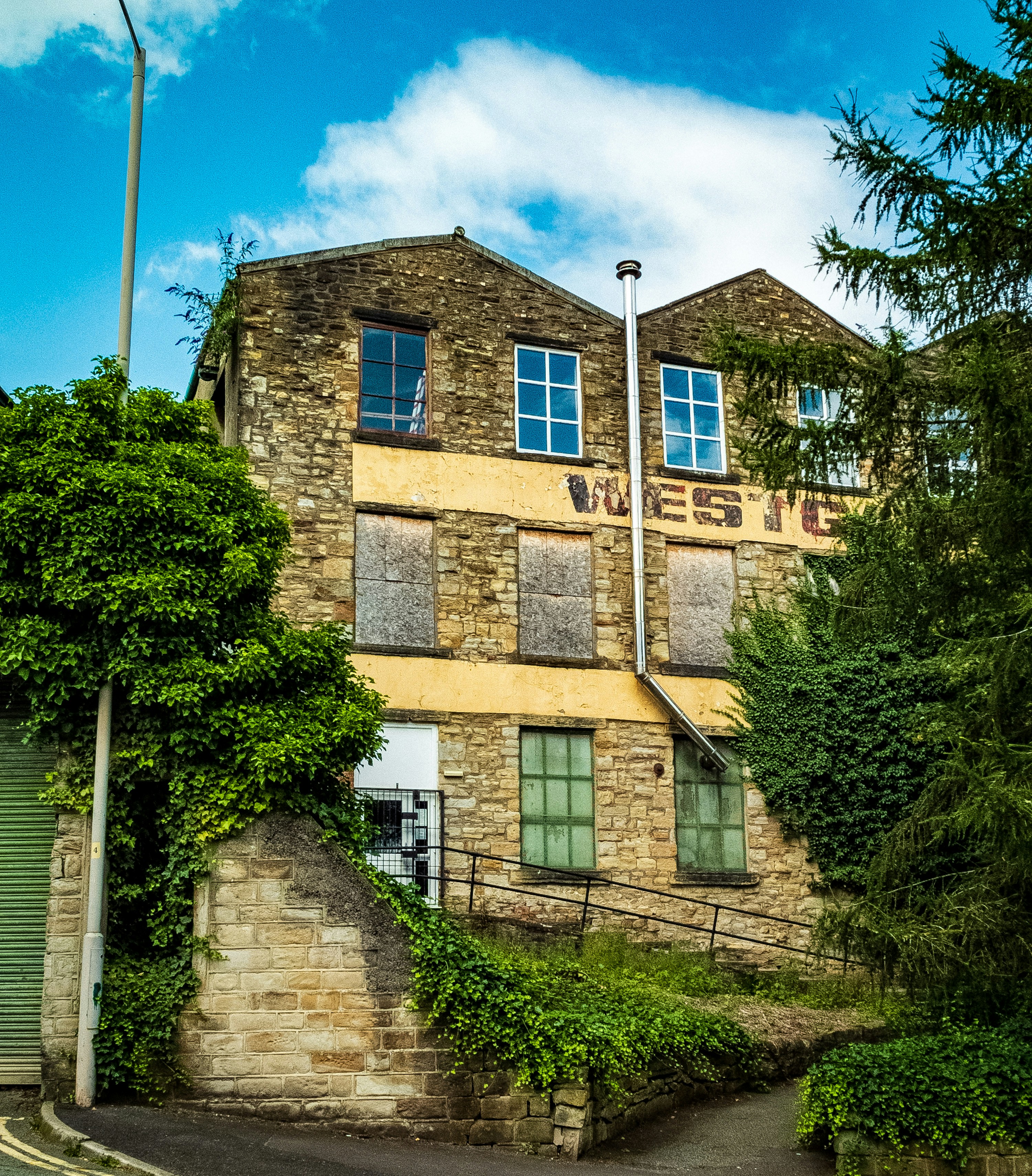 Stone storefront with ivy-clad stairs under a bright sky