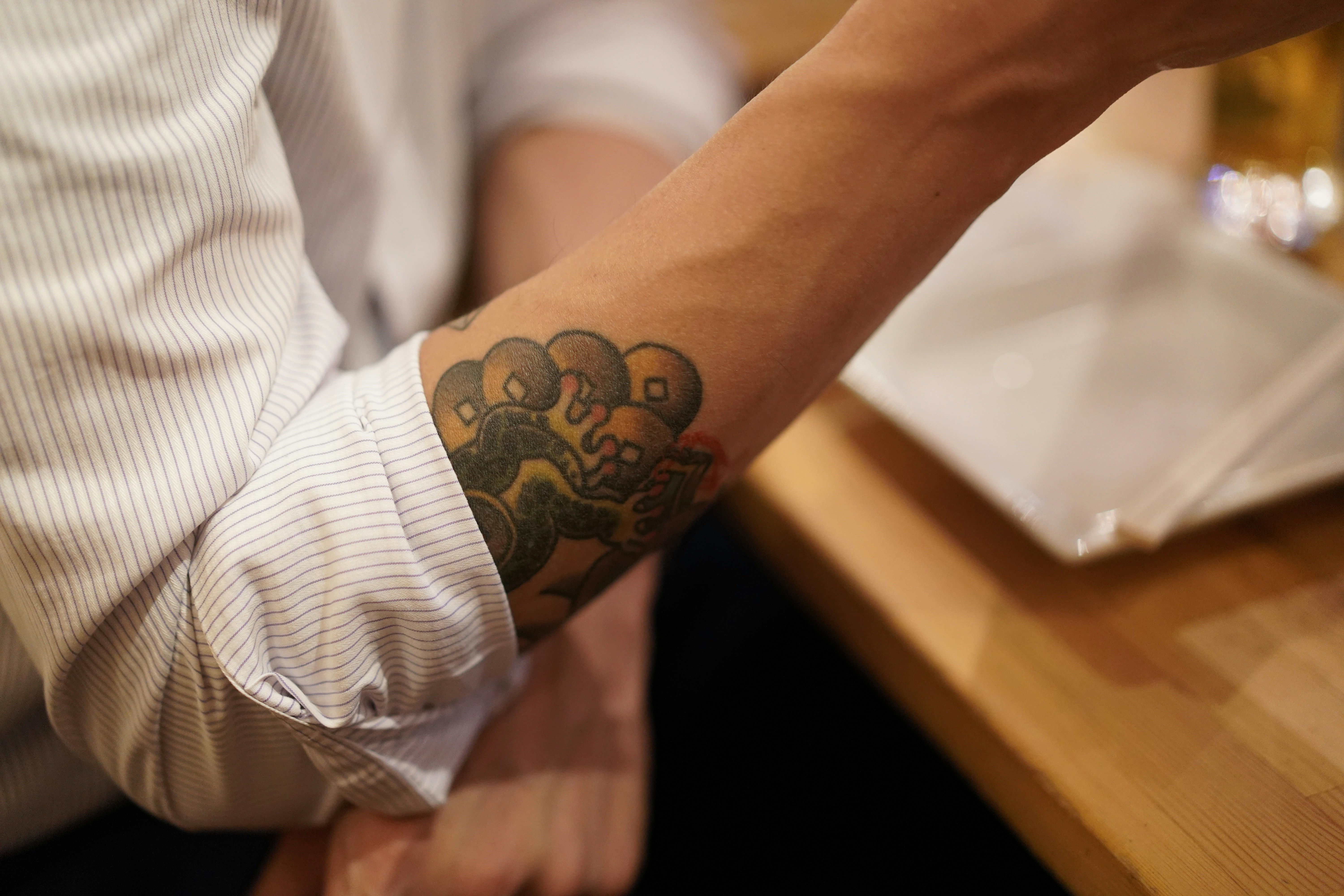 Ink in Quiet Light: A Tattooed Arm Resting by the Bar