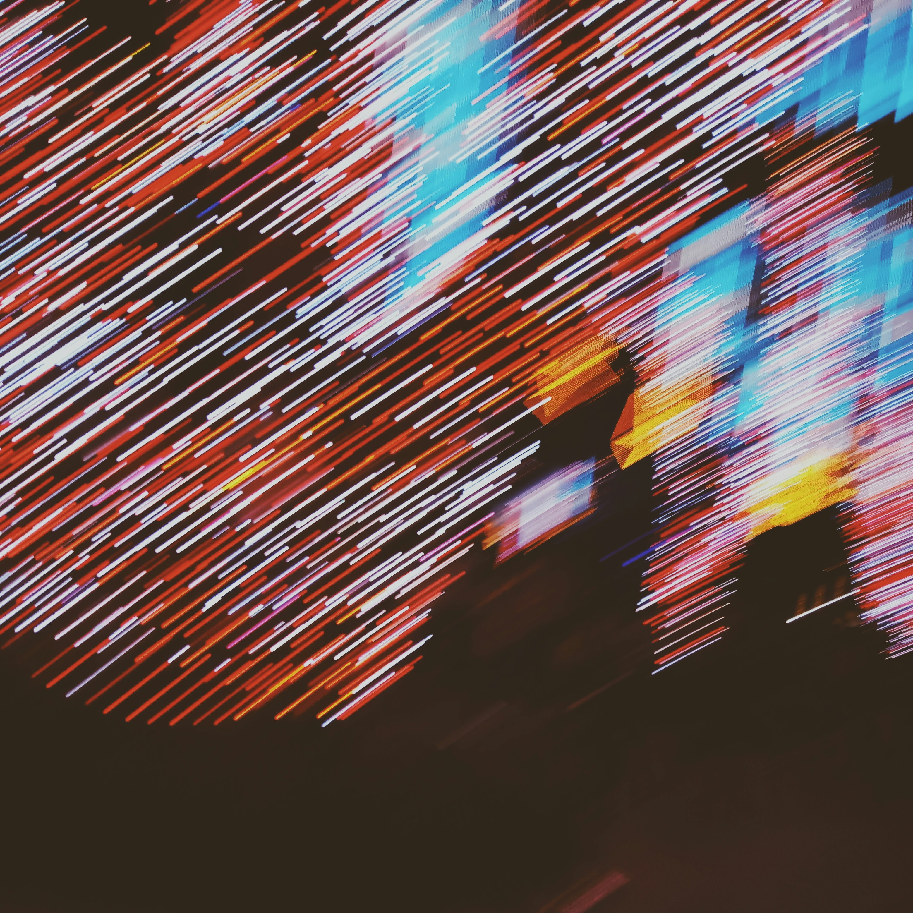 Vibrant streaks of colorful lights create a dynamic abstract scene, suggesting movement and energy during a festive event.