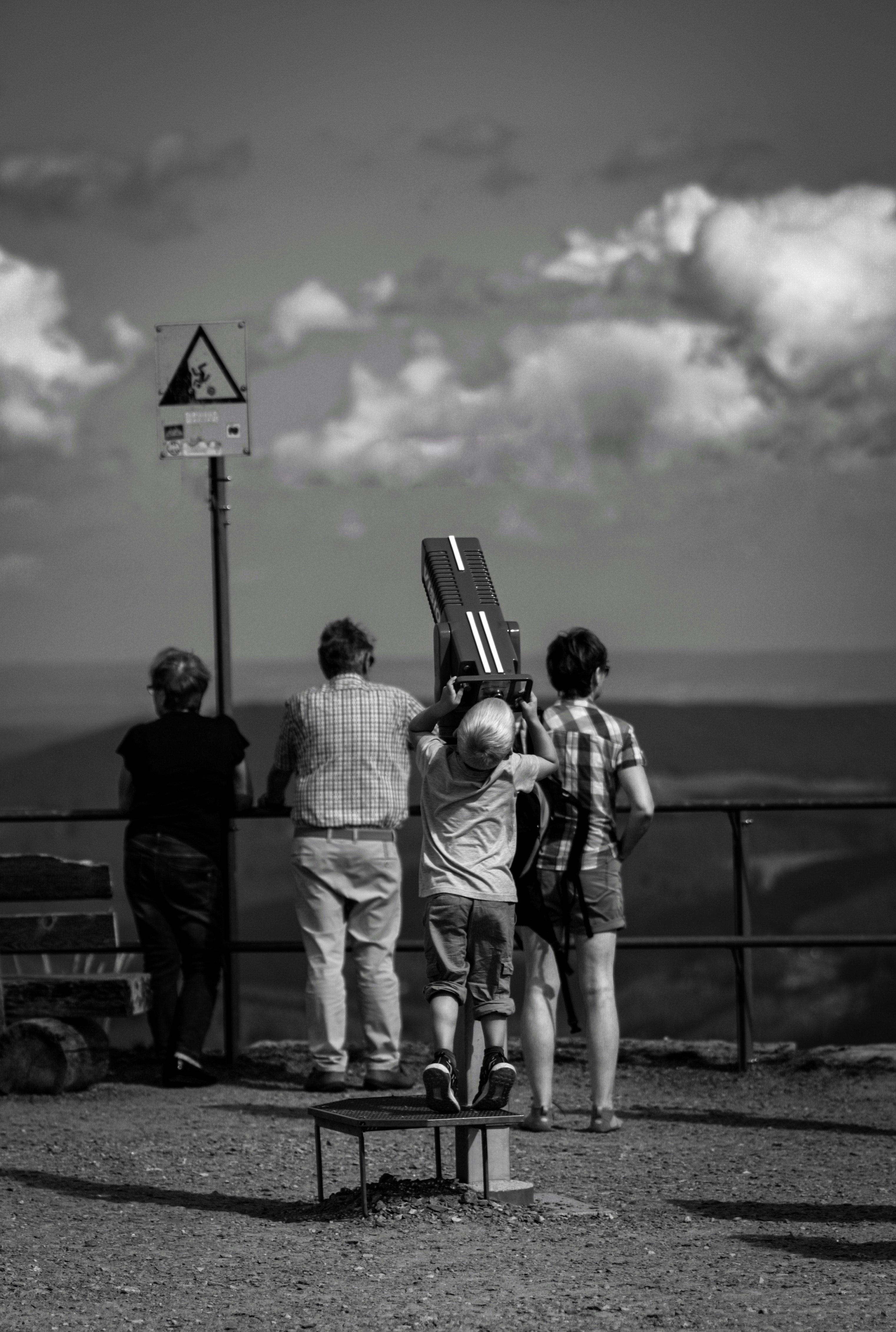 Grayscale photography of four person standing while looking on mountain ...