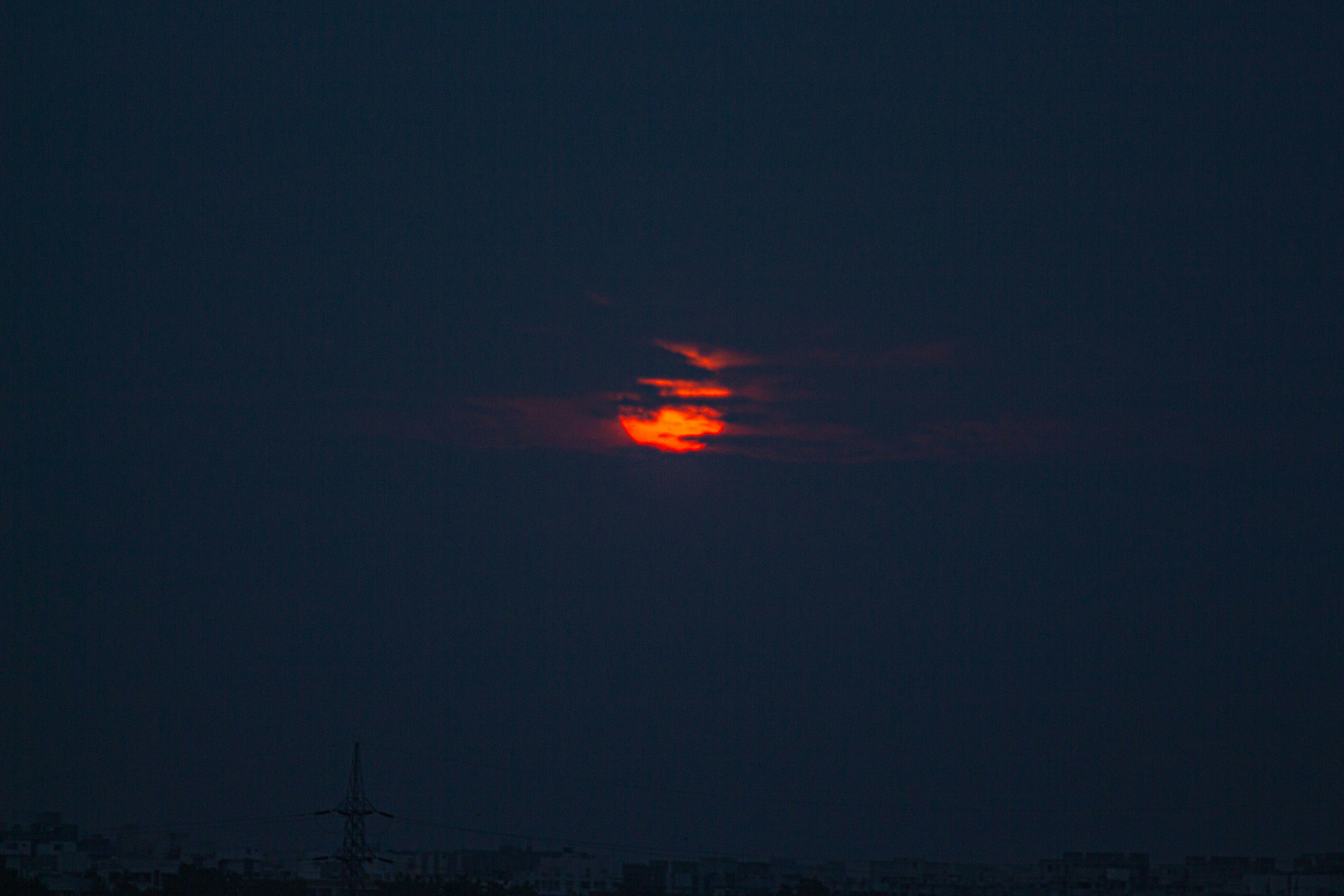 Crimson Dusk: City Silhouette Beneath a Subtle Sun
