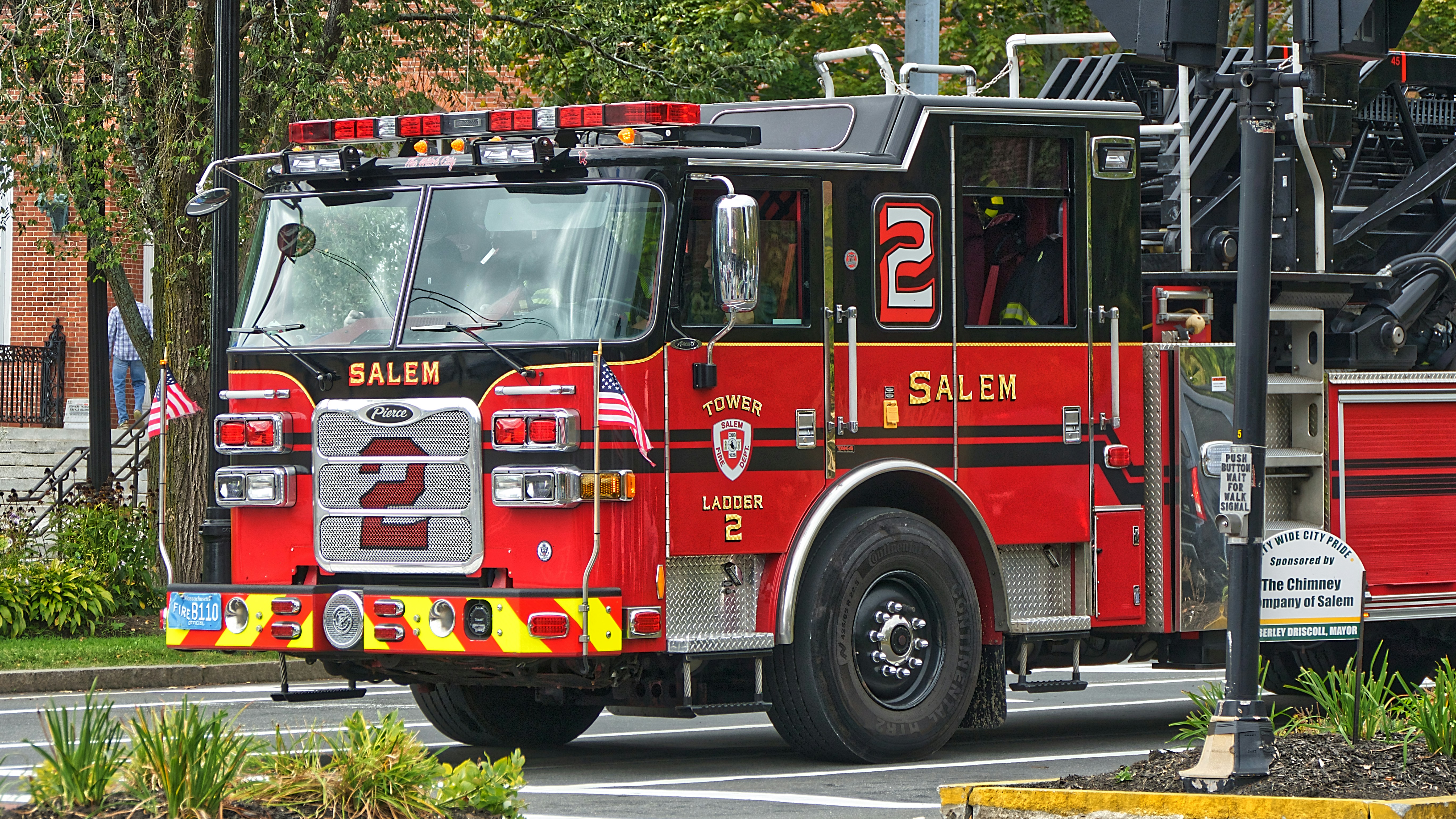 Red fire truck from Salem parked on a city street with greenery and buildings in the background.
