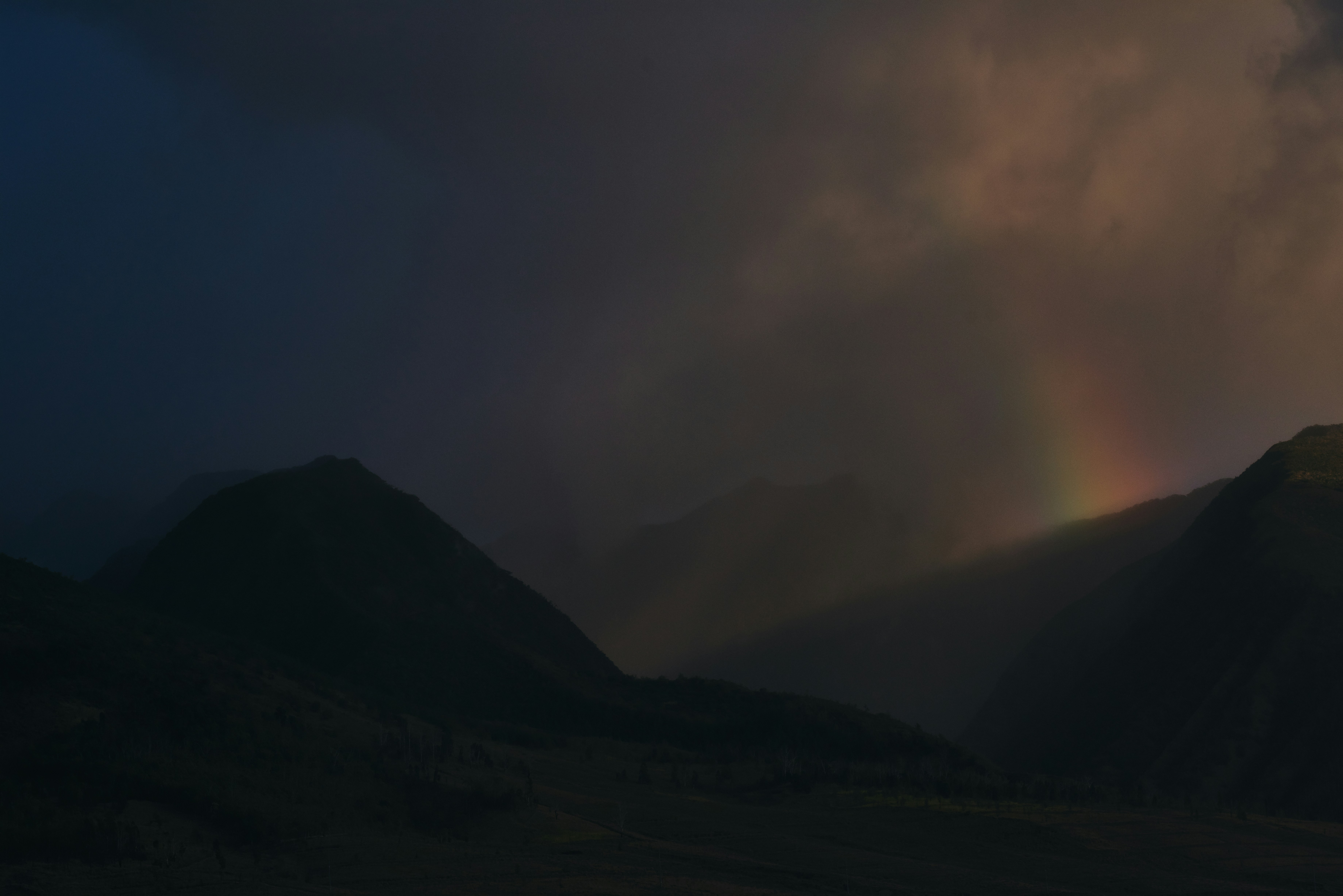 Rainbow and storm clouds over the West Maui Forest Reserve mountains near Lahaina, HI at sunset.