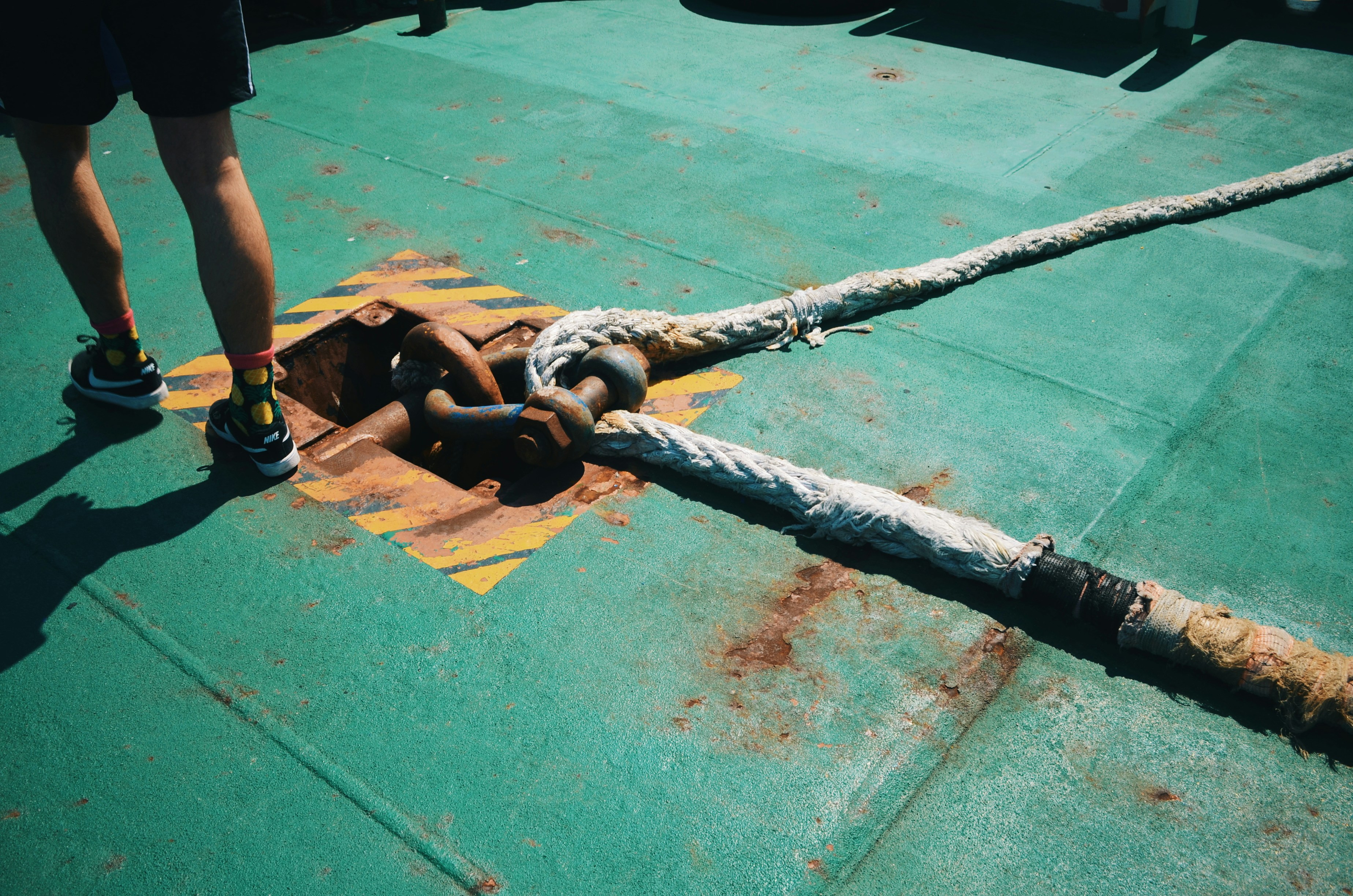 Teal Deck Mooring Ring: Ropes Looped and Ready on a Weathered Vessel